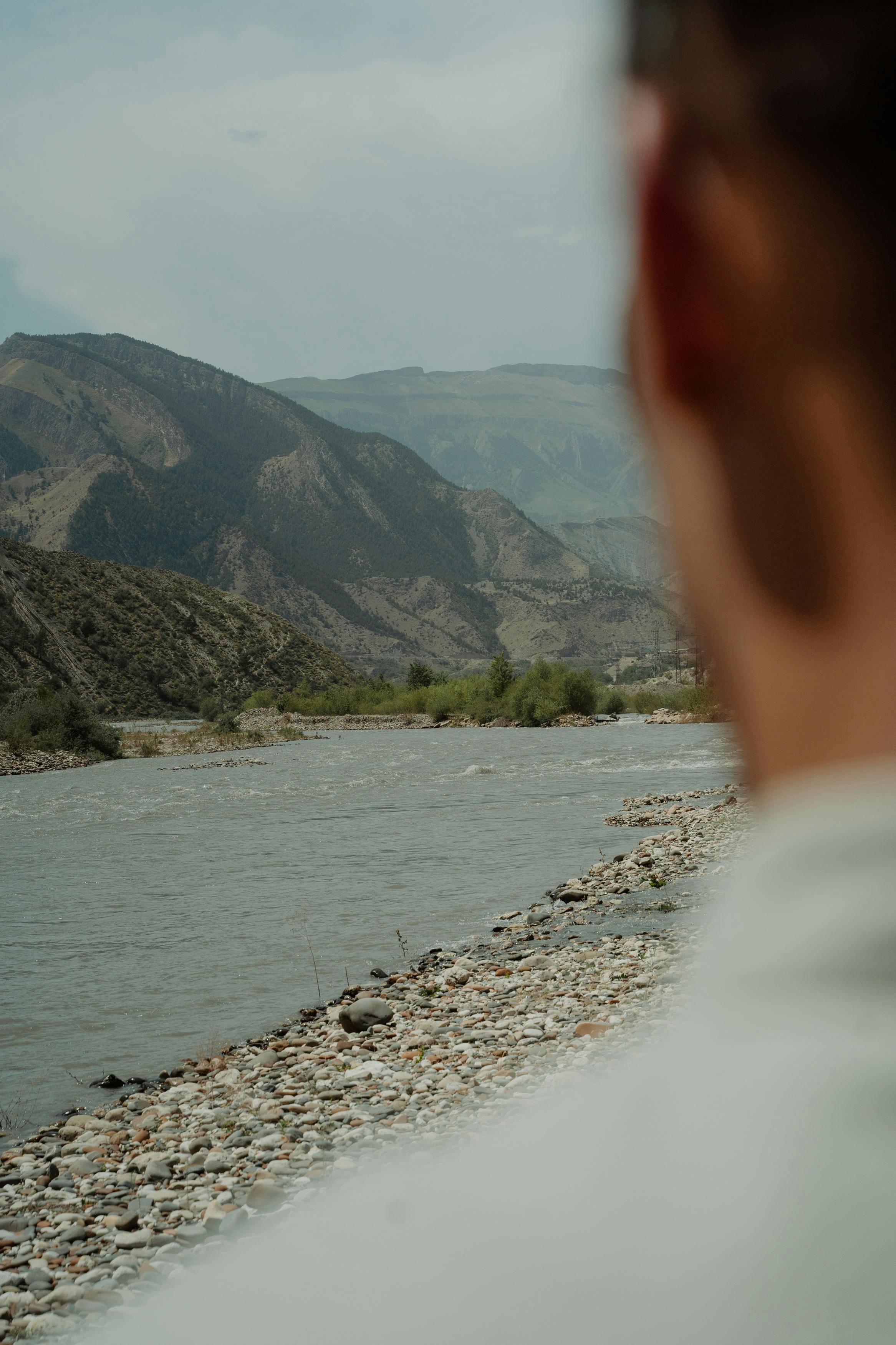 A Person Standing over the Rocky Riverside · Free Stock Photo