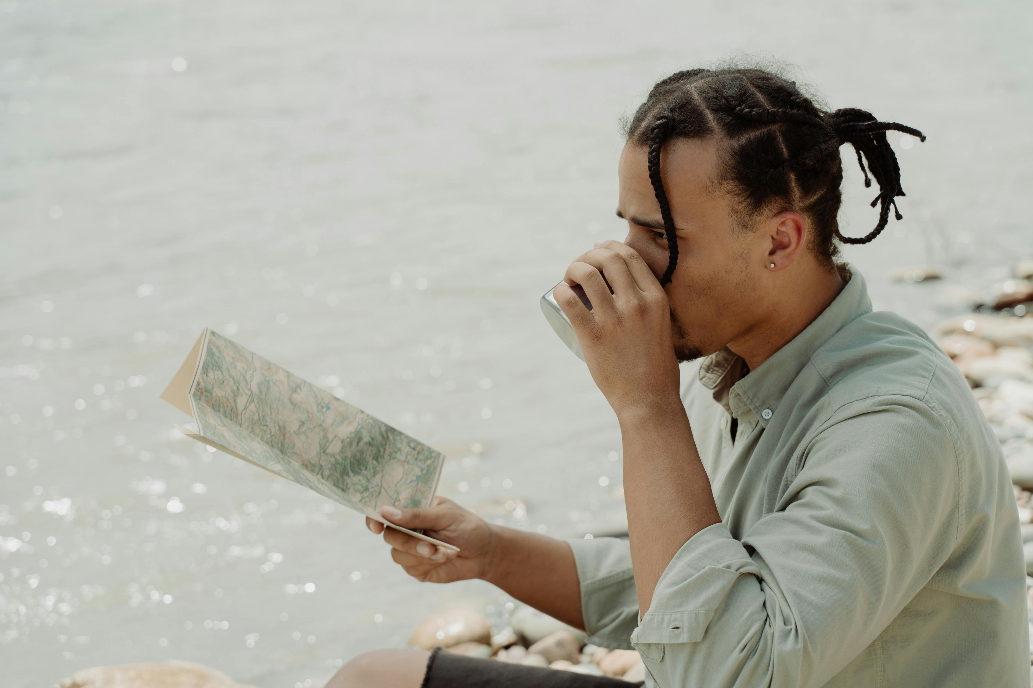 A Man Drinking on a Cup Holding a Map · Free Stock Photo