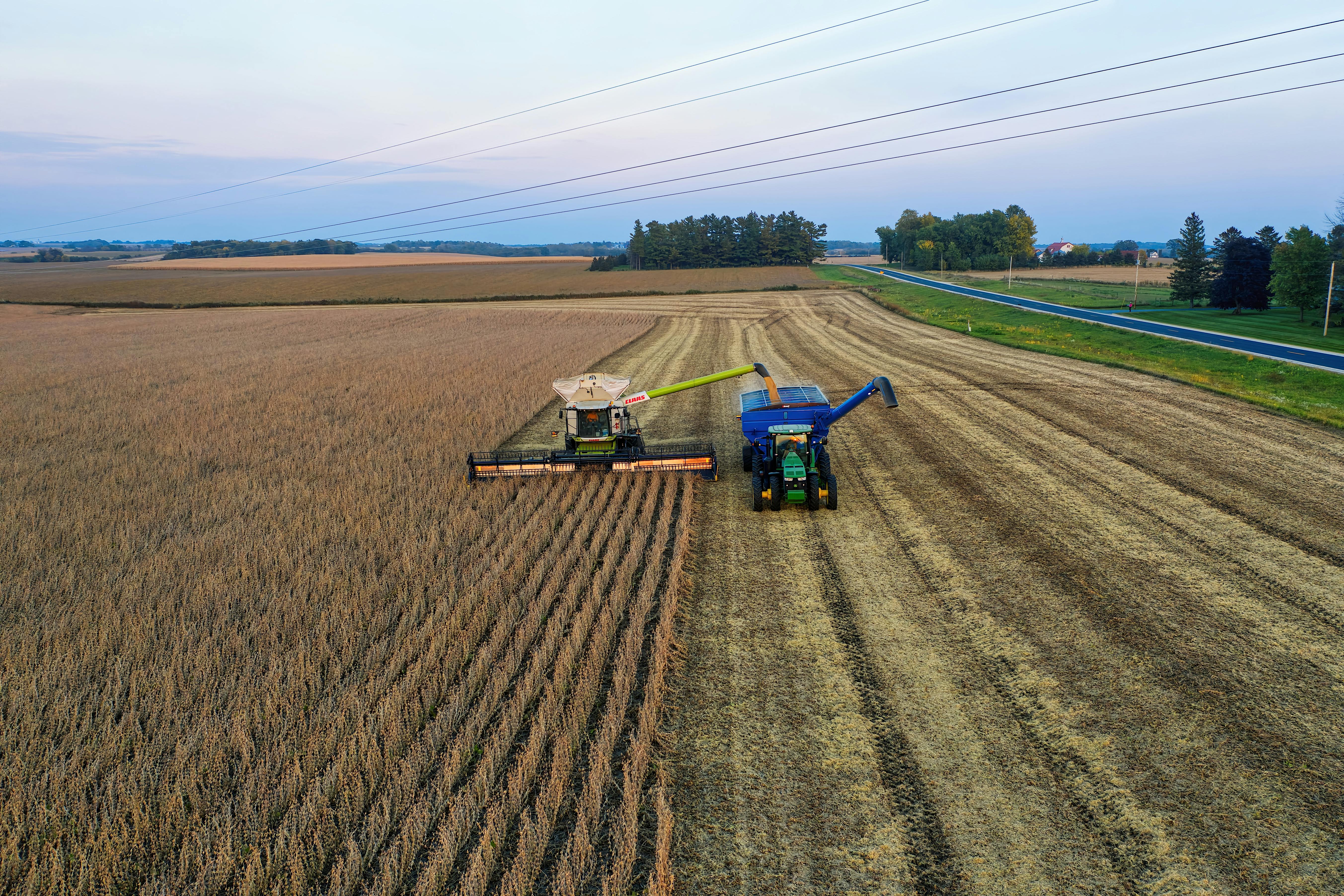 Combine Dumping Grain into Blue Trailer on Field · Free Stock Photo