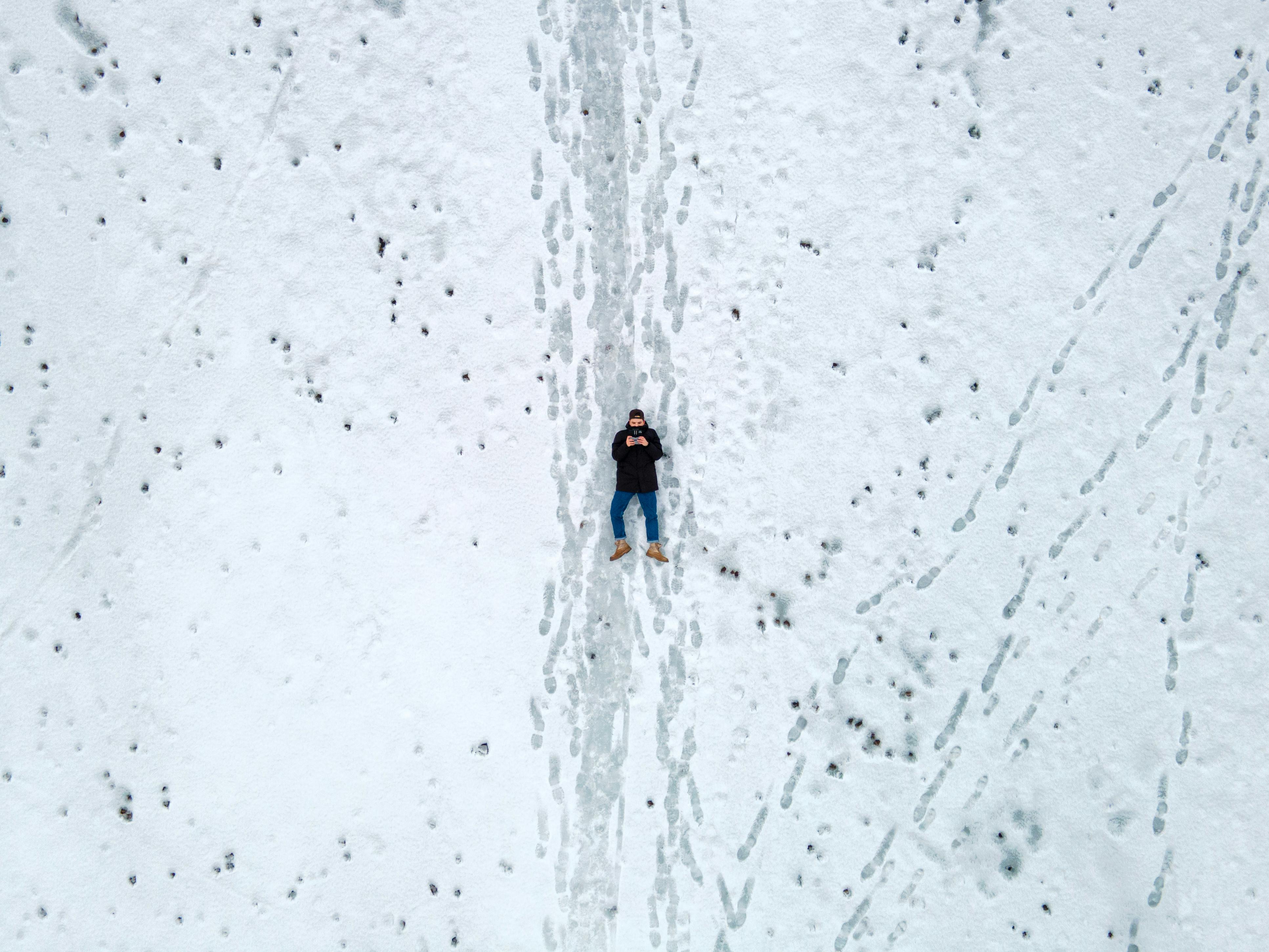 Person Lying Down on Snow Covered Ground · Free Stock Photo
