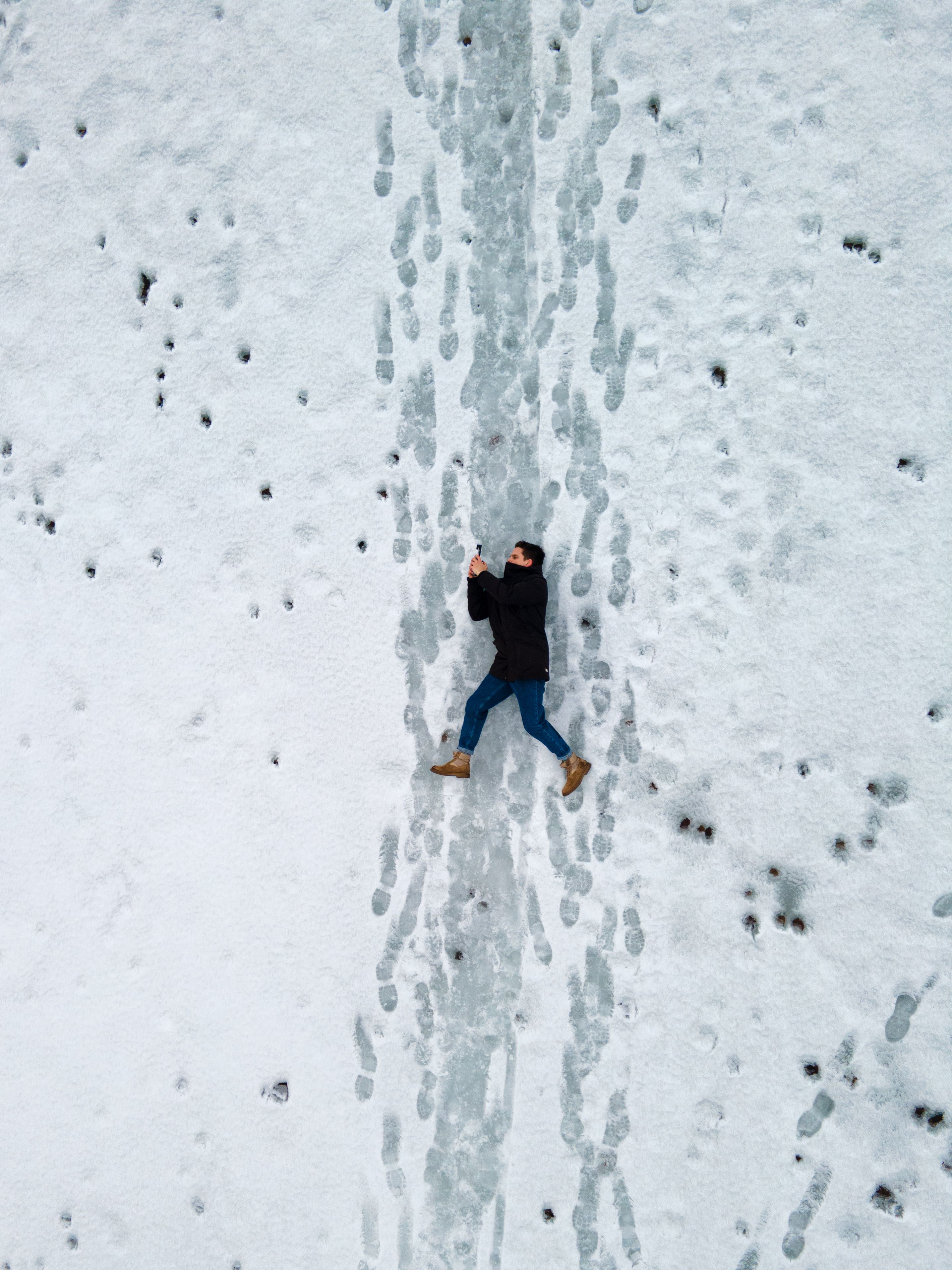 A Person Lying Down on the Snow Covered Ground · Free Stock Photo