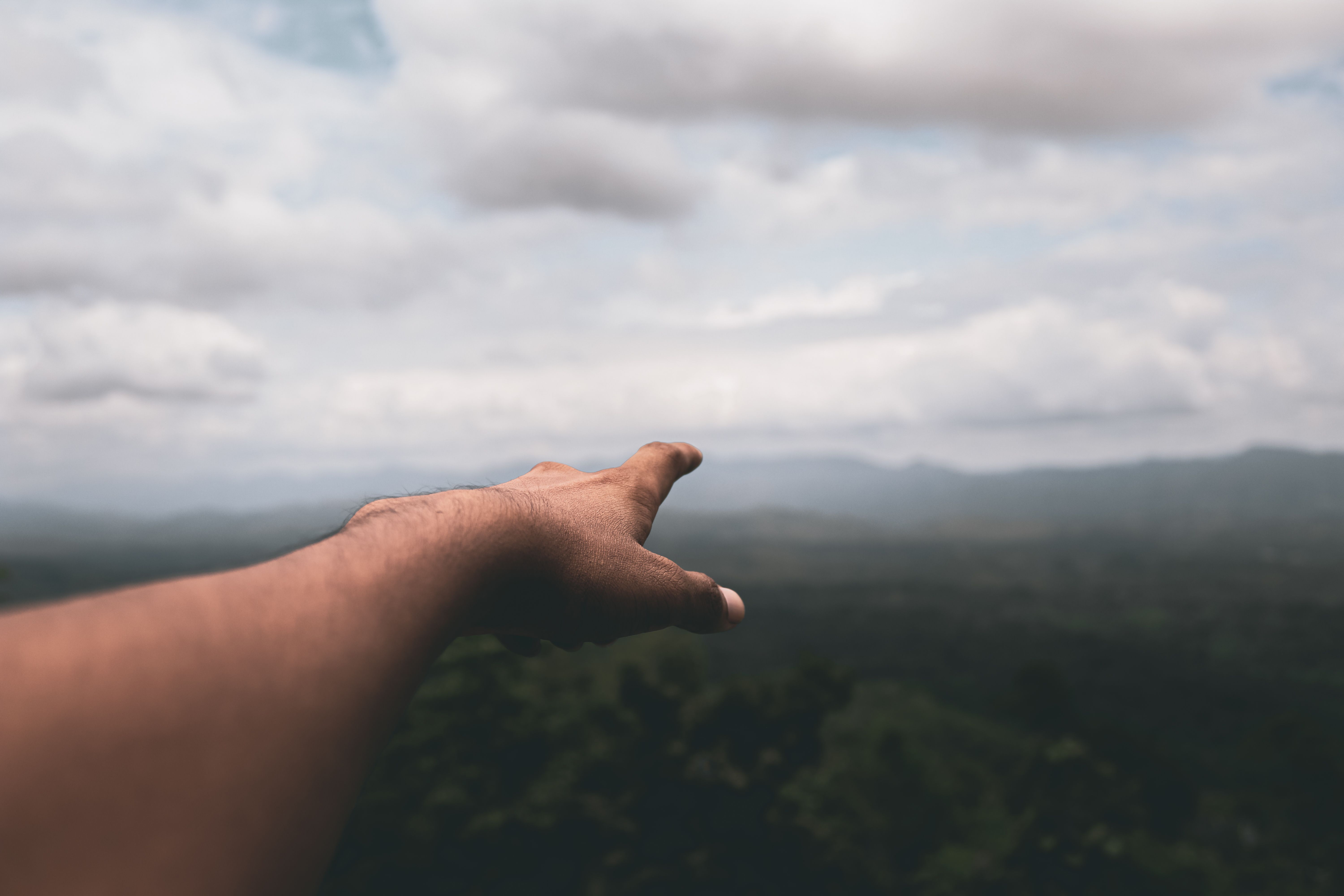 Hand over Blurred Landscape · Free Stock Photo
