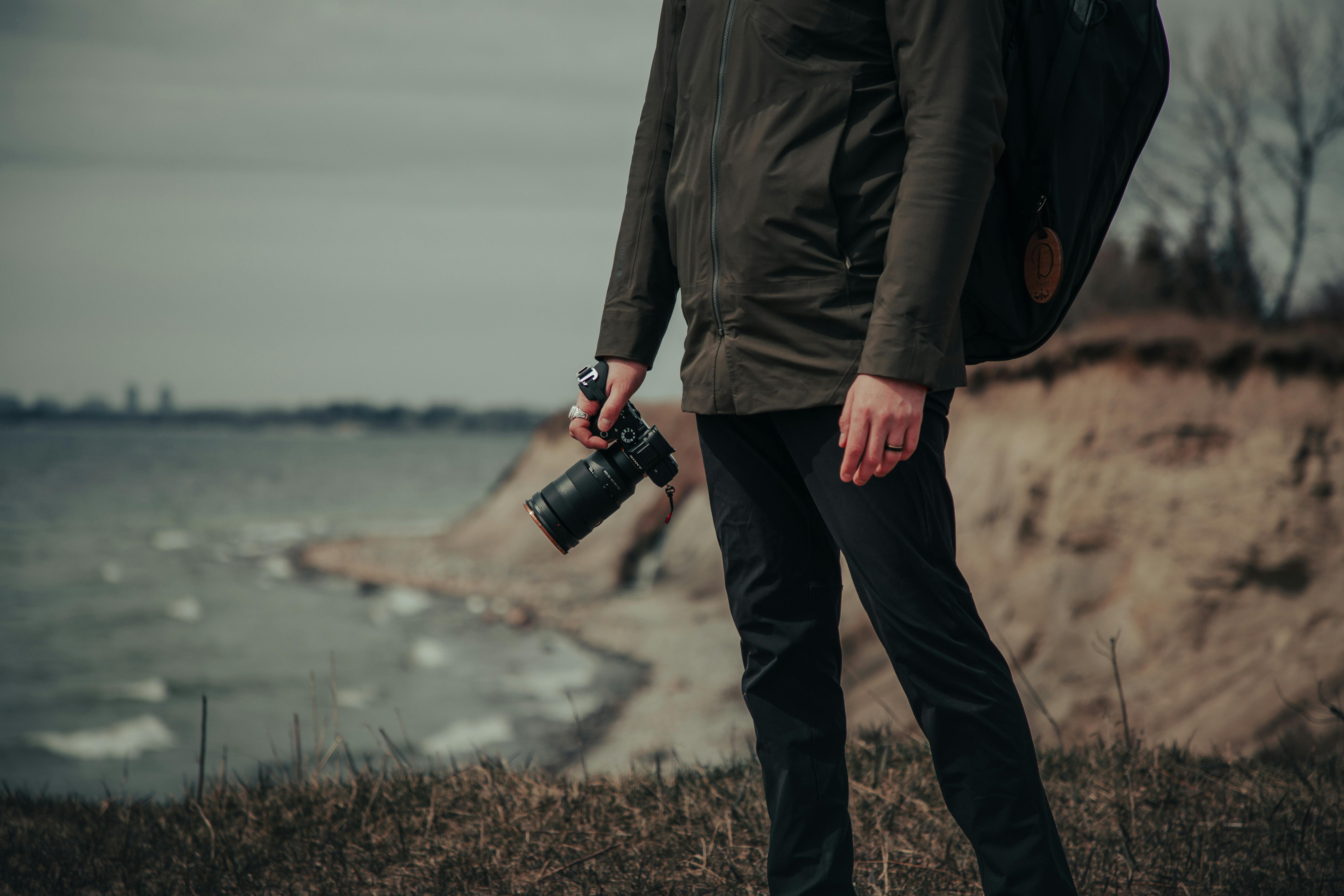 Standing Man in Jacket Holding Camera · Free Stock Photo