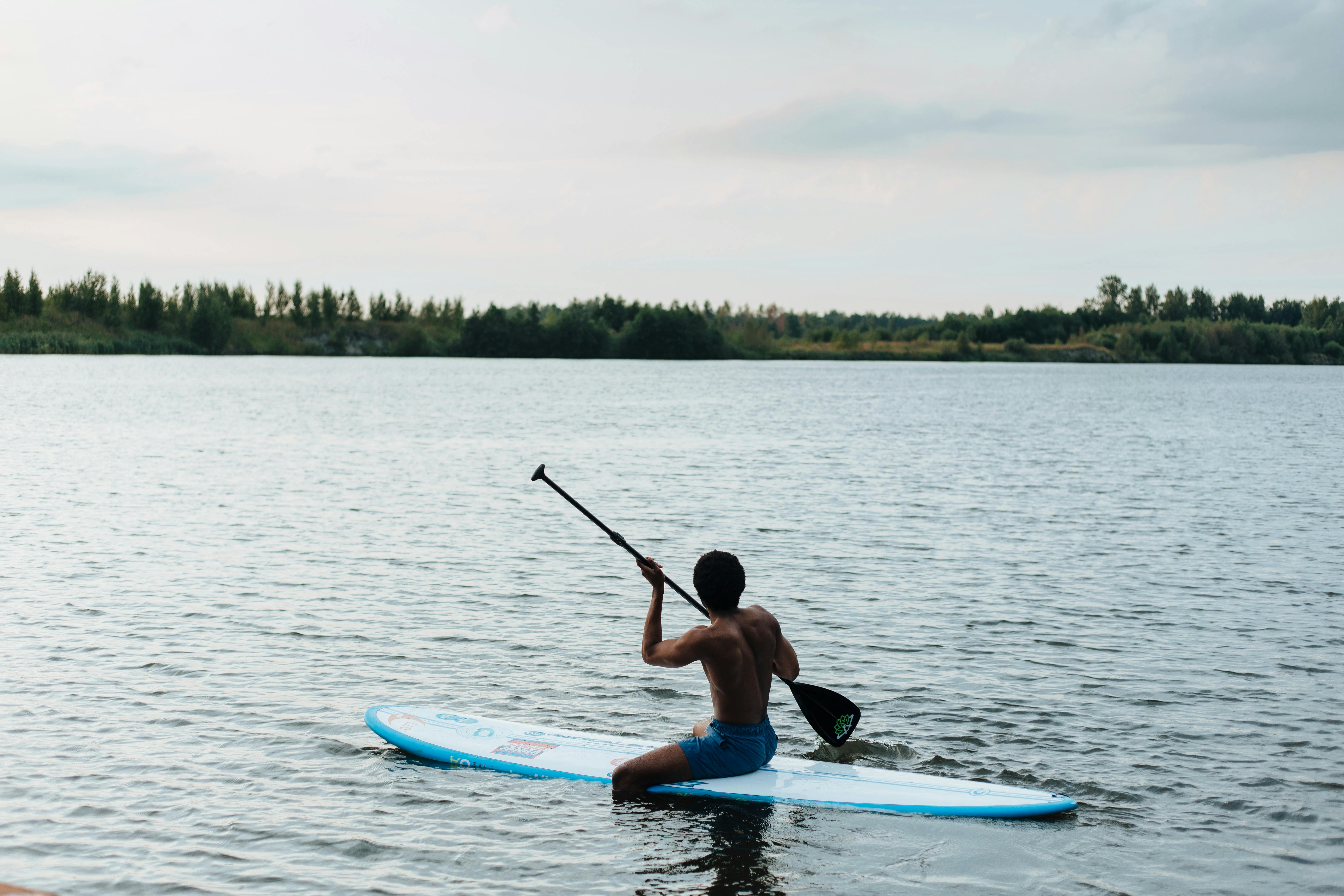 Man Sitting on Paddleboard and Rowing · Free Stock Photo