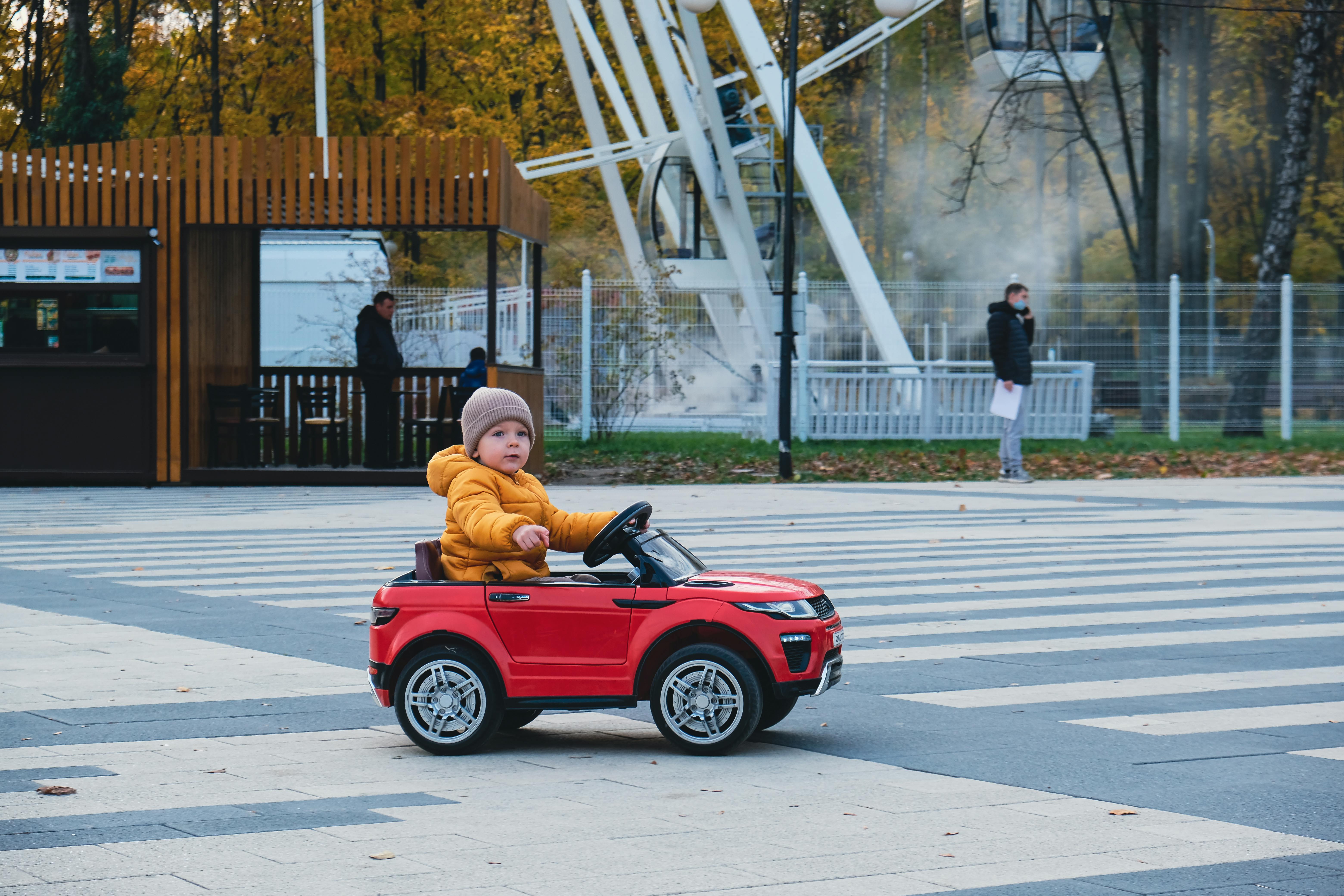A Child Riding a Toy Car in the Street · Free Stock Photo