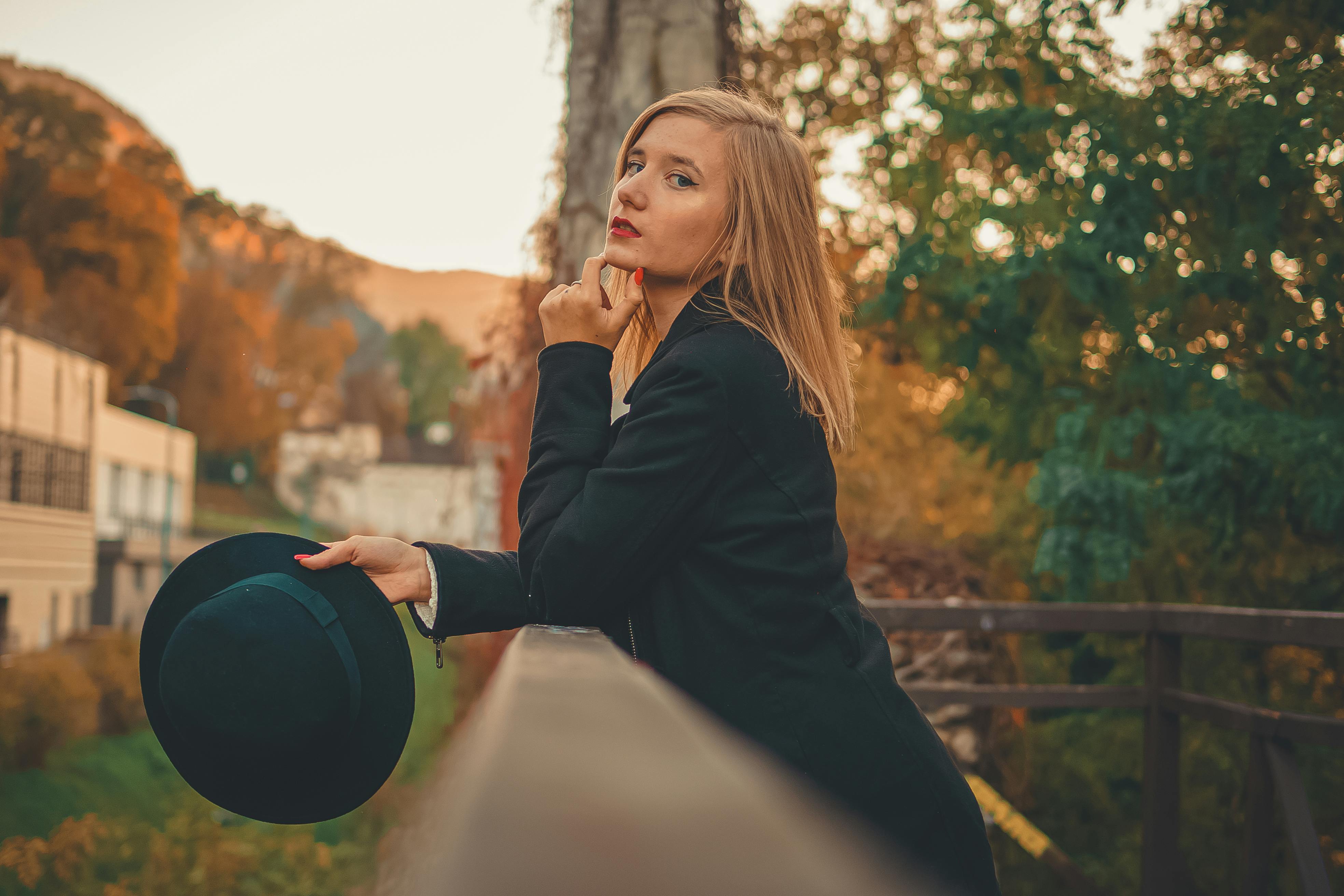Person Leaning on Railing While Holding a Hat · Free Stock Photo