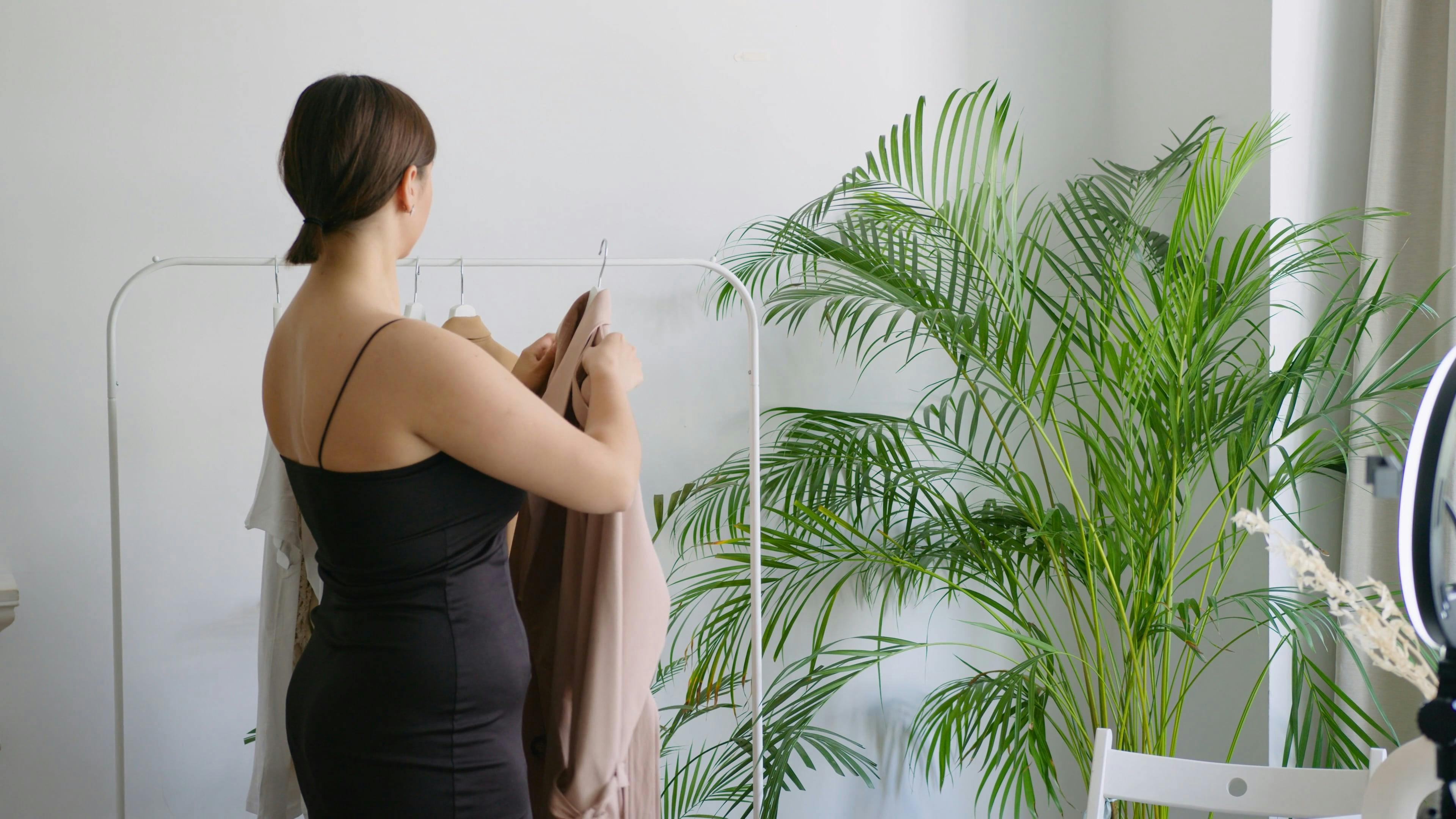 A Young Woman Hanging a Trench Coat on a Clothing Rack Free Stock Video ...