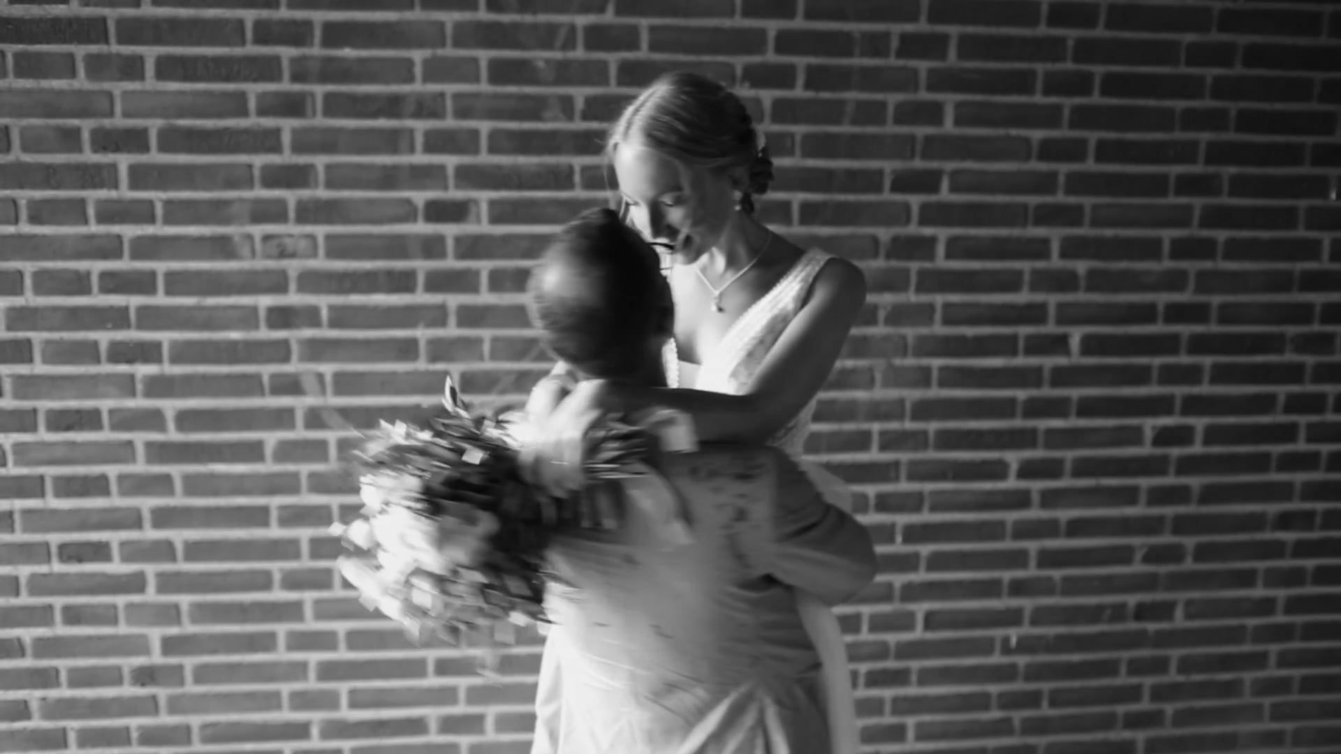 A bride and groom hugging in front of a brick wall Free Stock Video ...