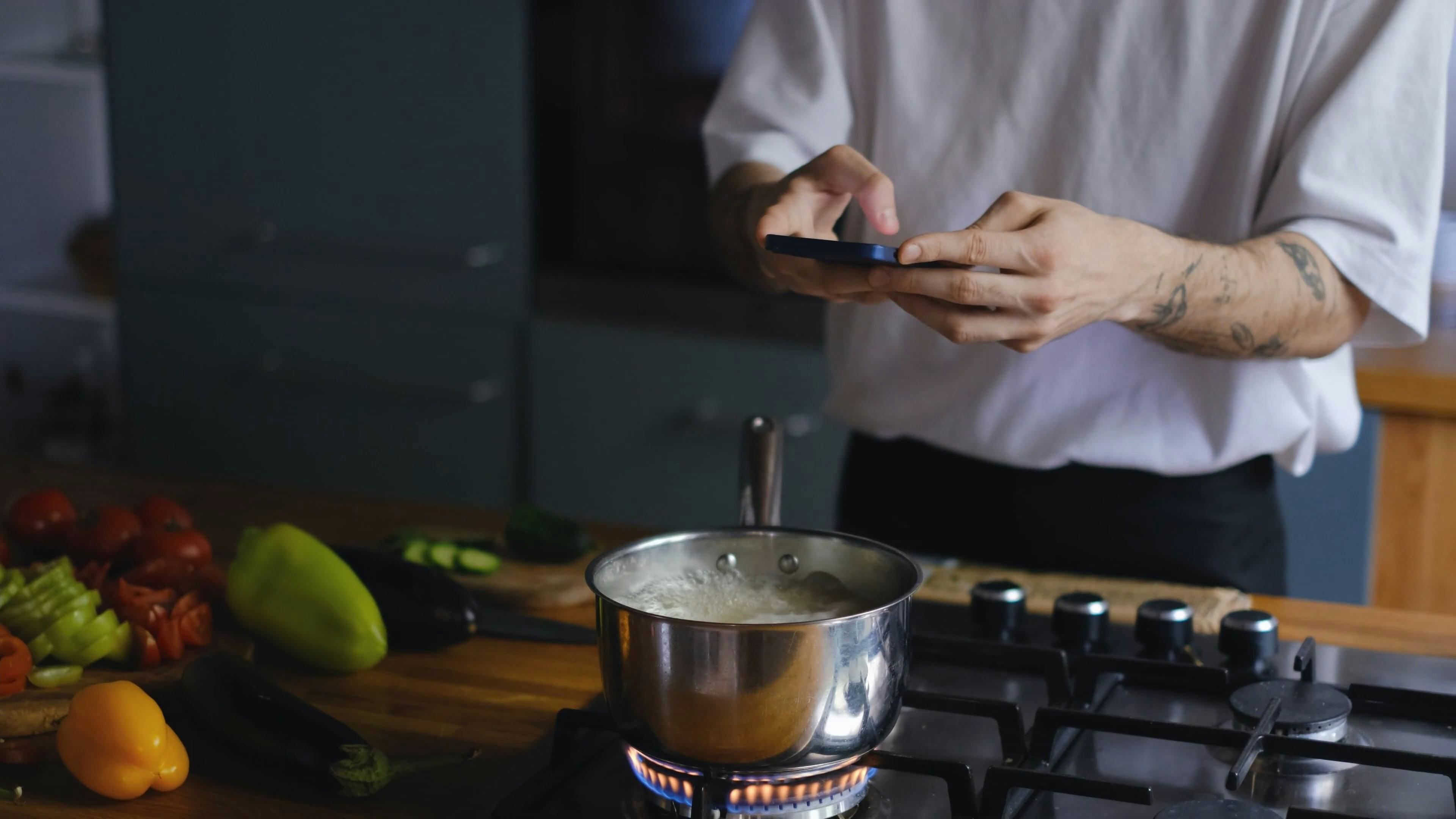 A Person Cooking Pasta and Recording a Video with a Smartphone Free ...