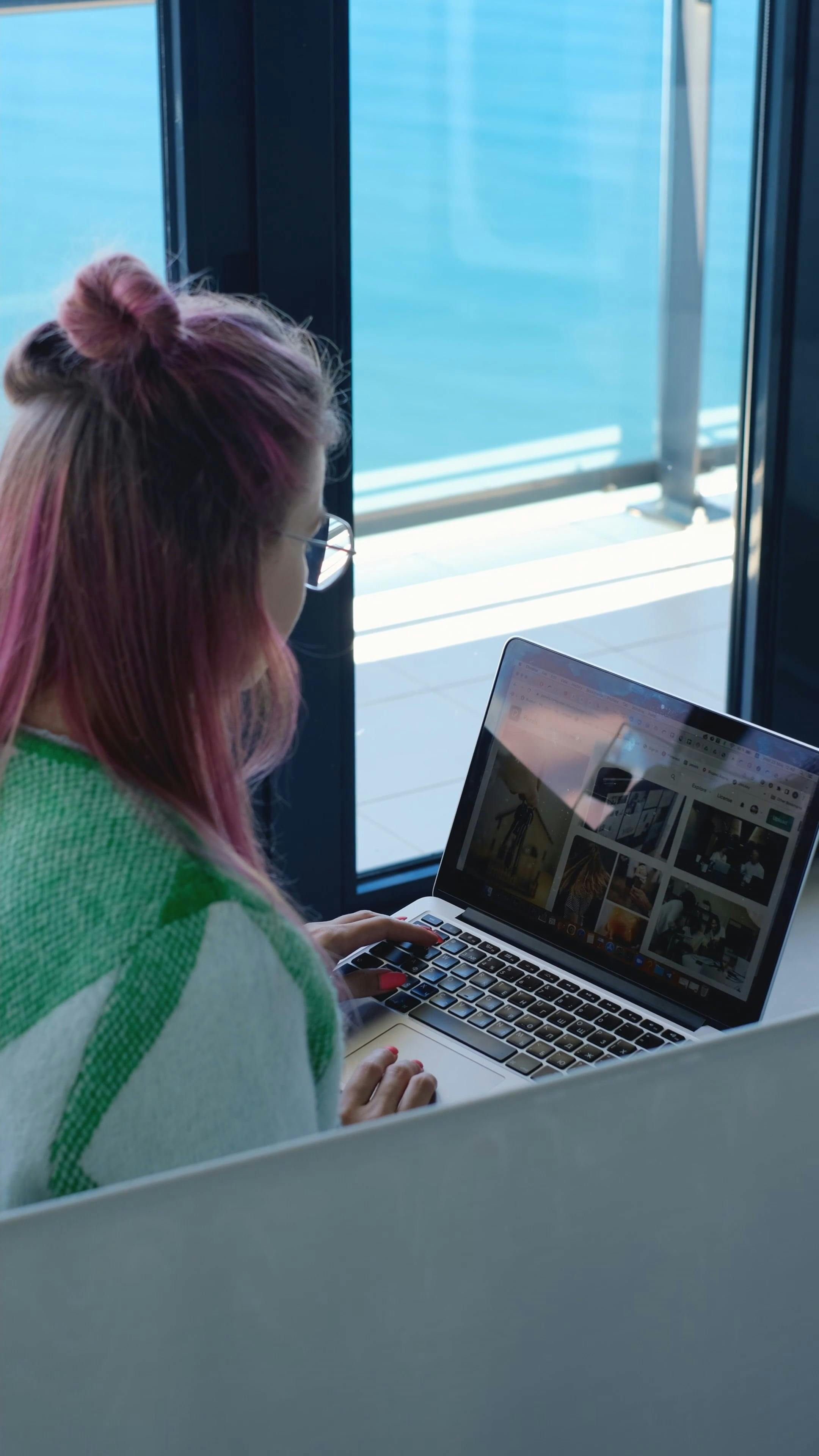 A Young Woman Sitting by a Window Using a Laptop Free Stock Video ...