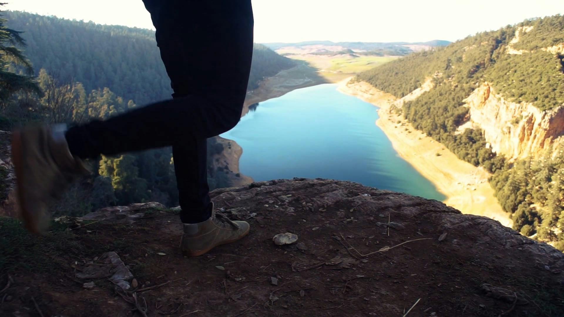 A Person Standing on a Mountain Kicking a Rock into a Lake Free Stock ...