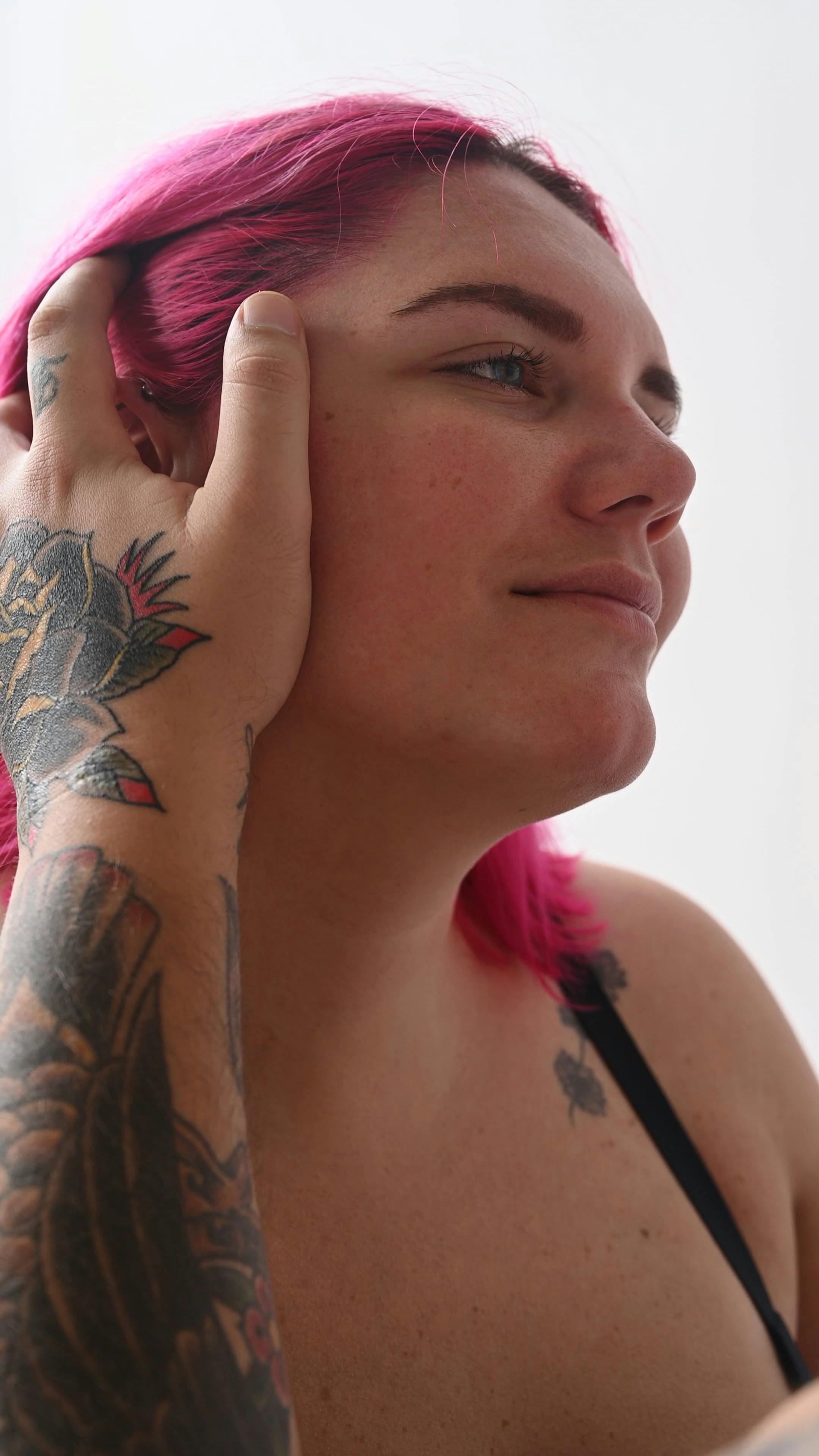 A Tattooed Hand Caressing the Face of a Smiling Woman with Pink Hair ...