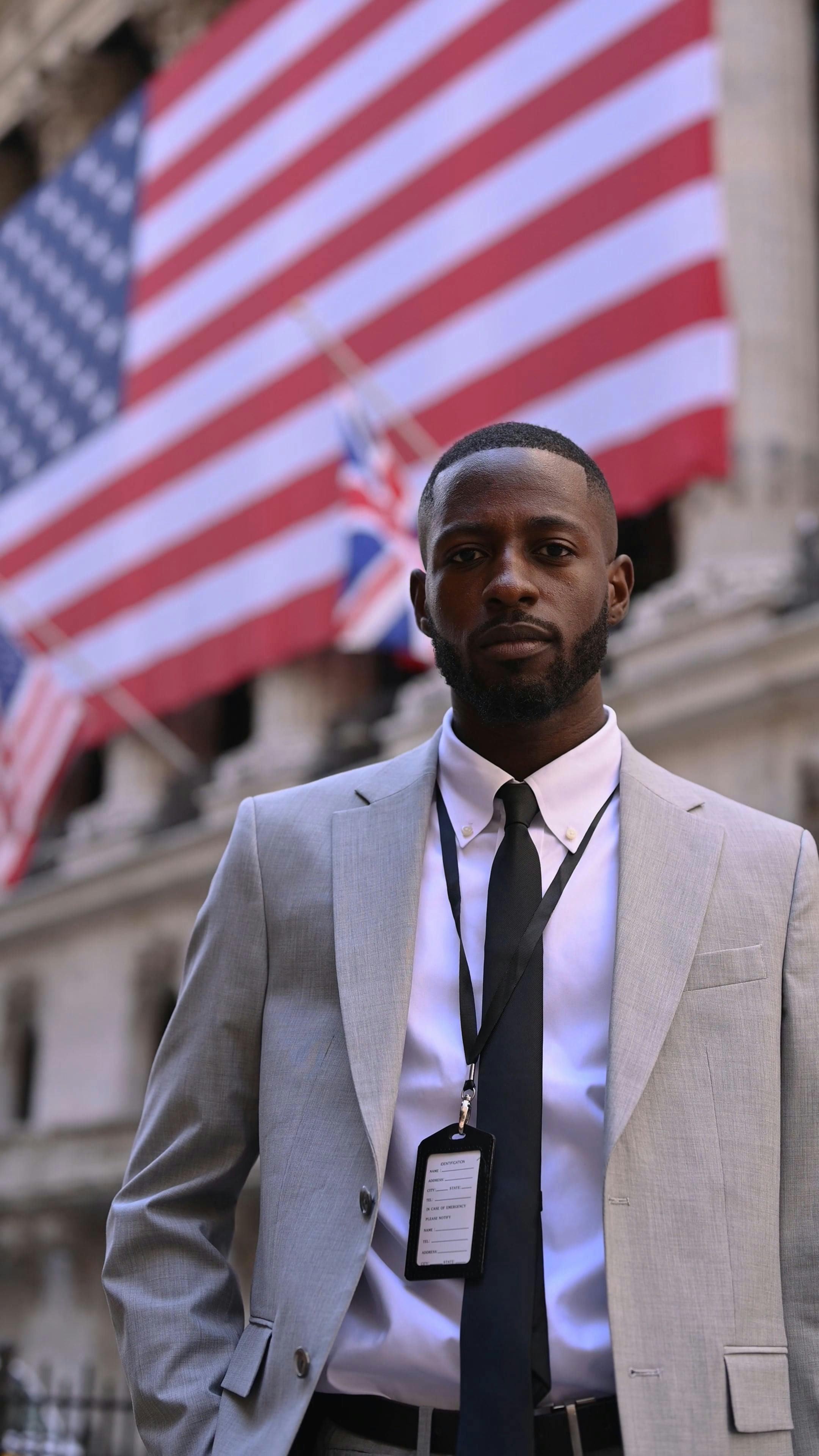 A Man in a Suit Posing in front of a Building with the United States ...