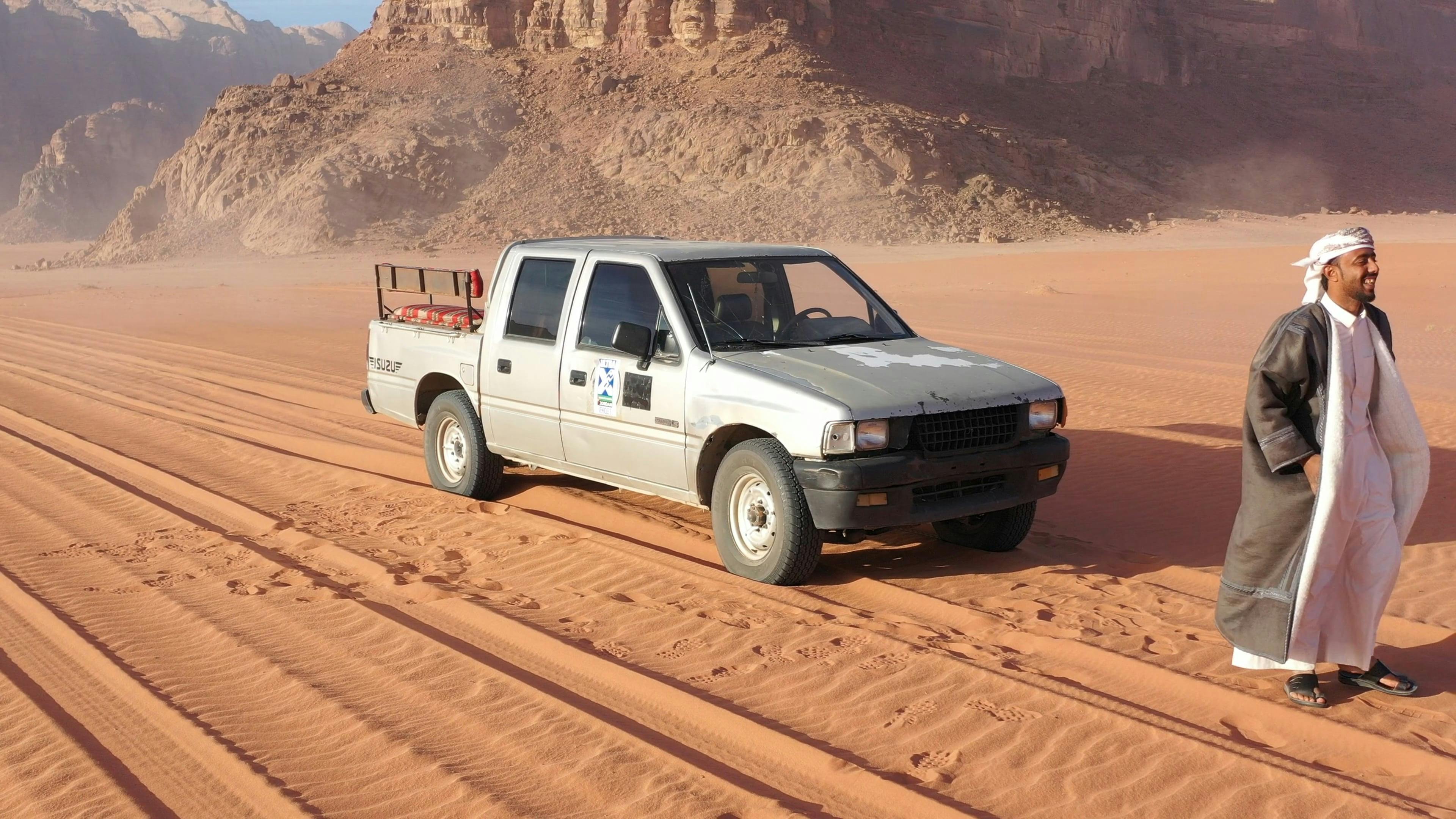A Man in a Tunic and a Headscarf Posing in front of a Pick up Truck in ...