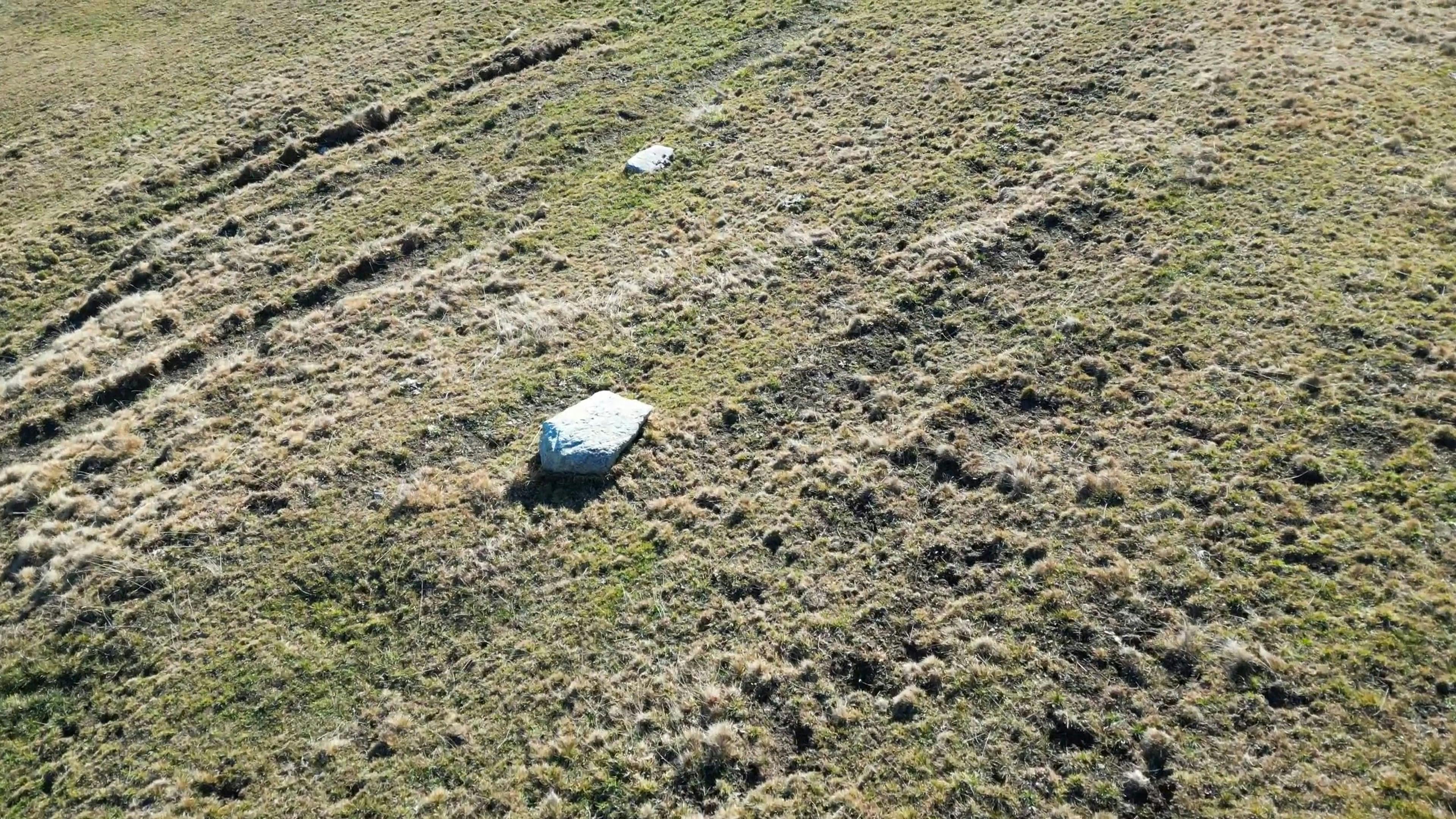 A Drone Footage of a Grass Field Near the Mountain Under the Blue Sky ...