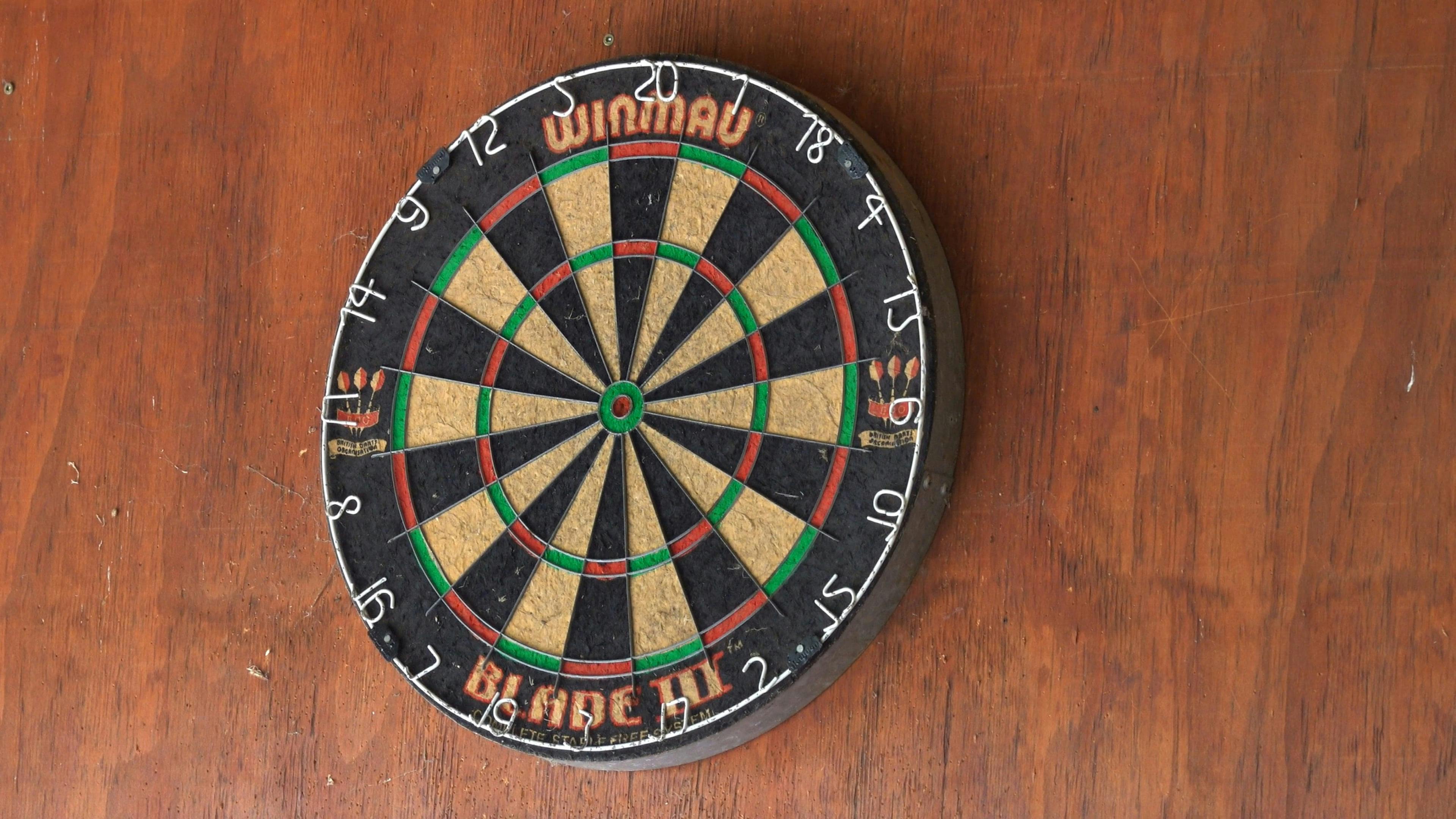 A dart board on a wooden wall with a black and green dart Free Stock ...