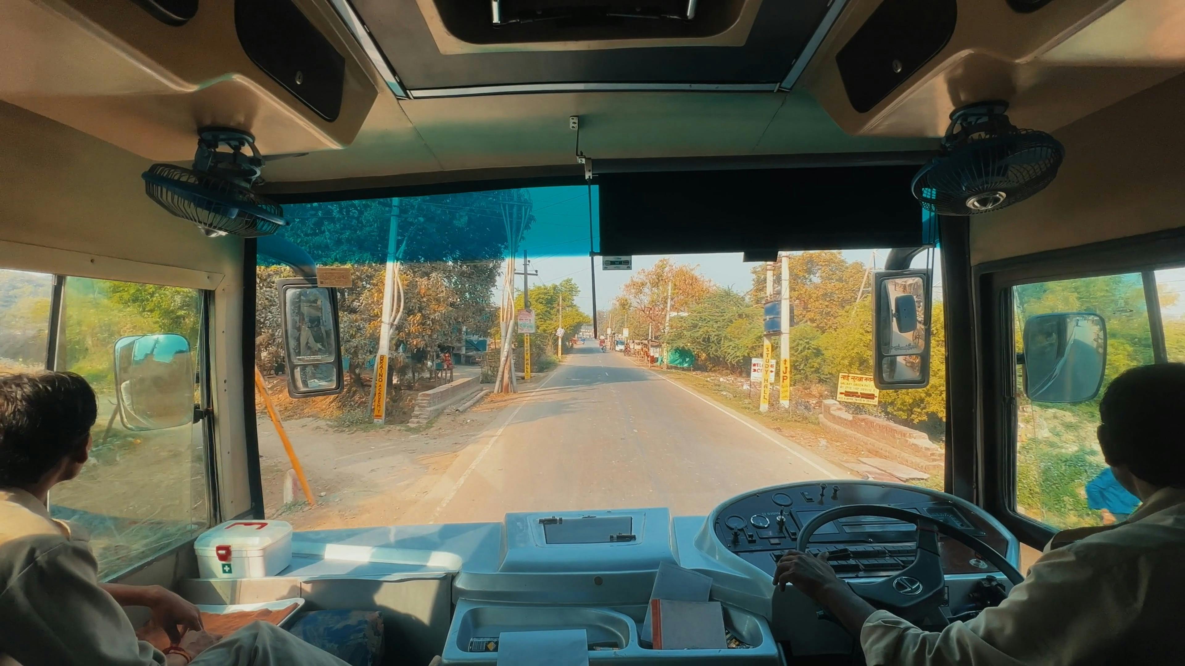 A bus driver is driving down a road with two people in the back Free ...