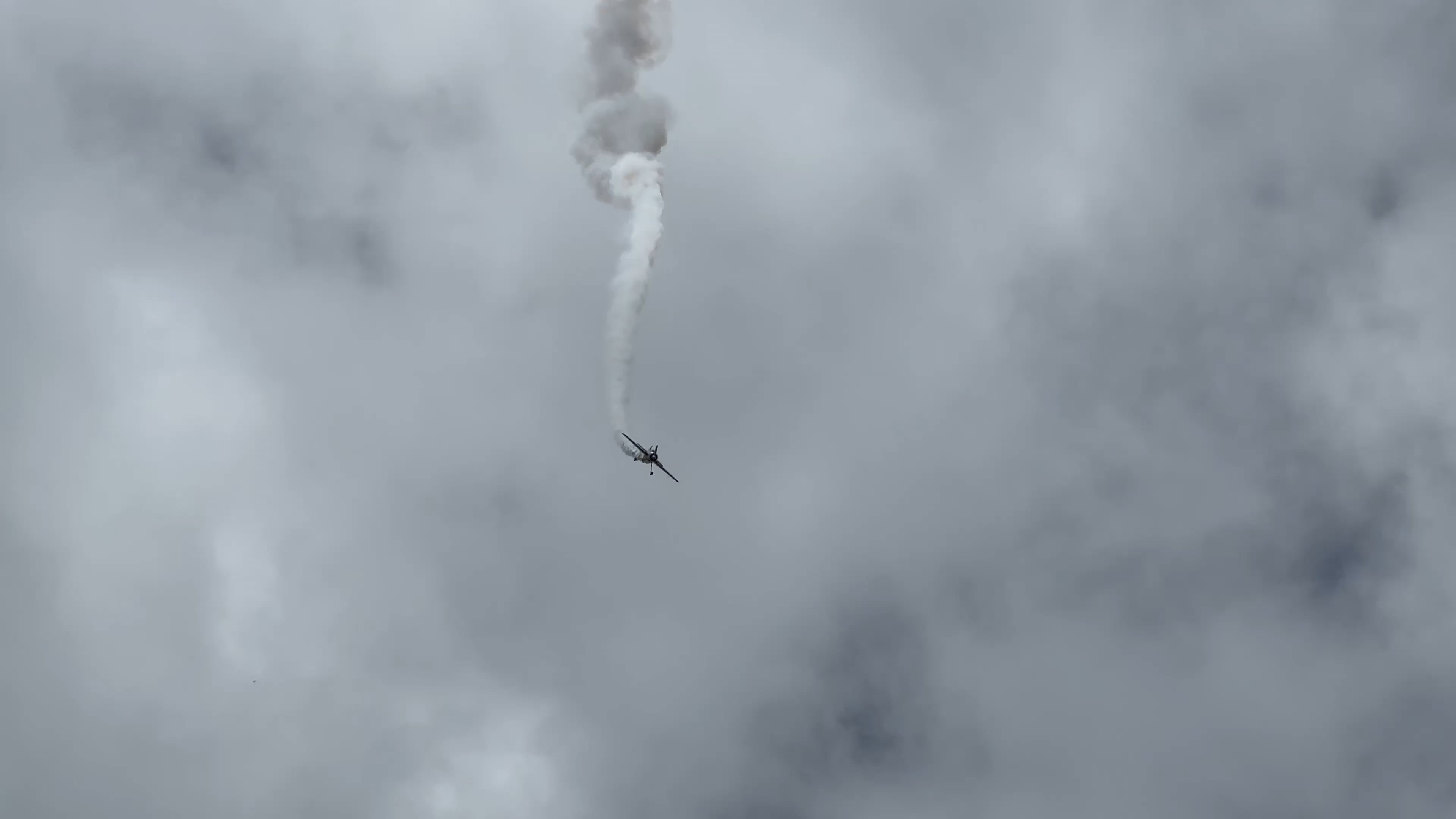 A small airplane flying through the air with smoke trailing behind it ...