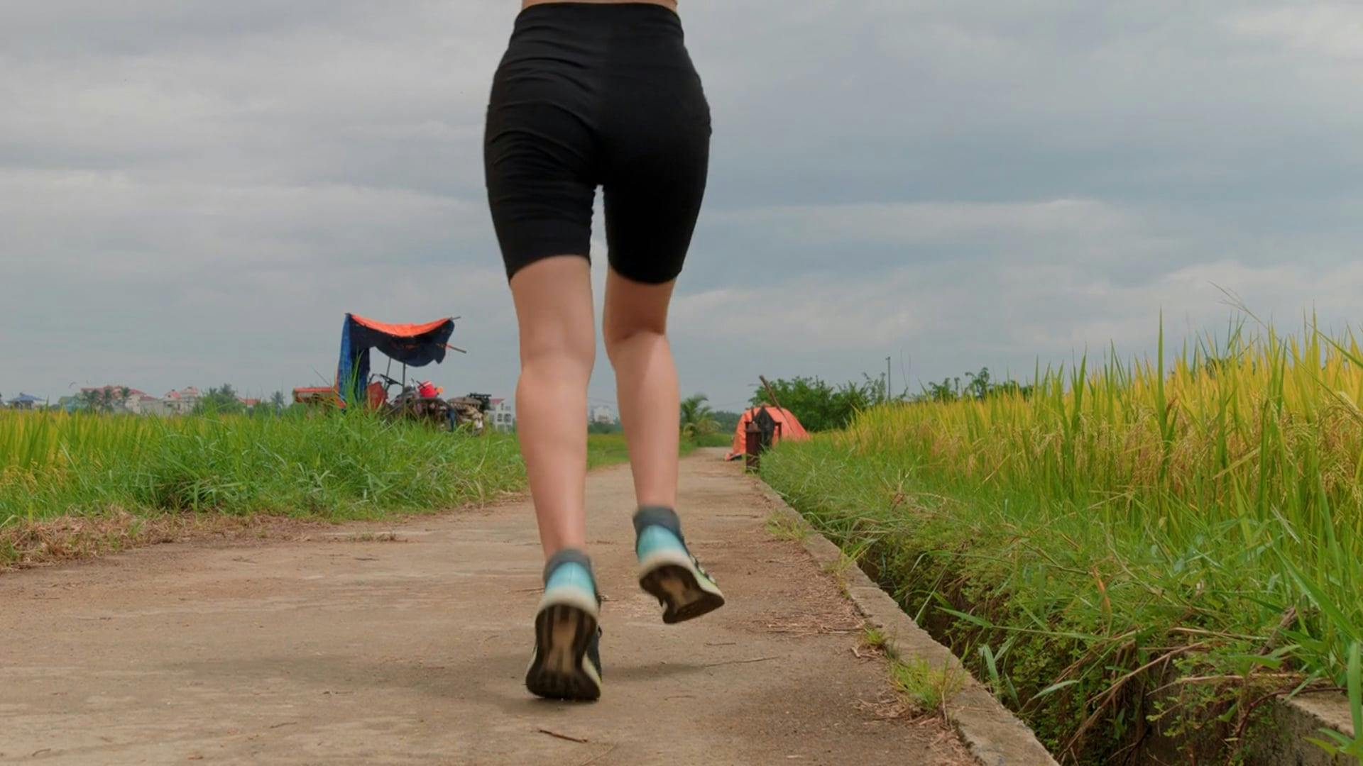 A woman running down a path in a rice field Free Stock Video Footage ...