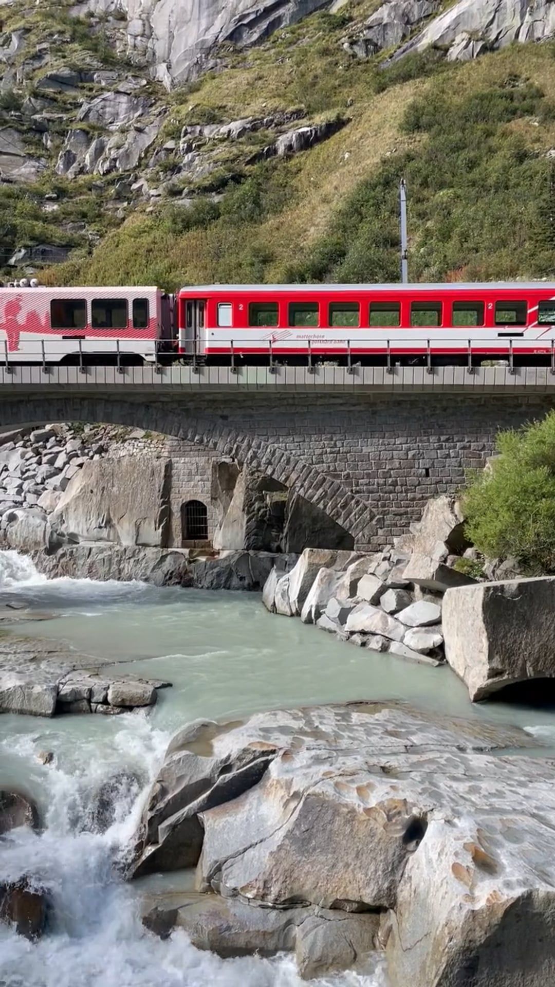A train traveling through a mountain pass with water flowing below Free ...