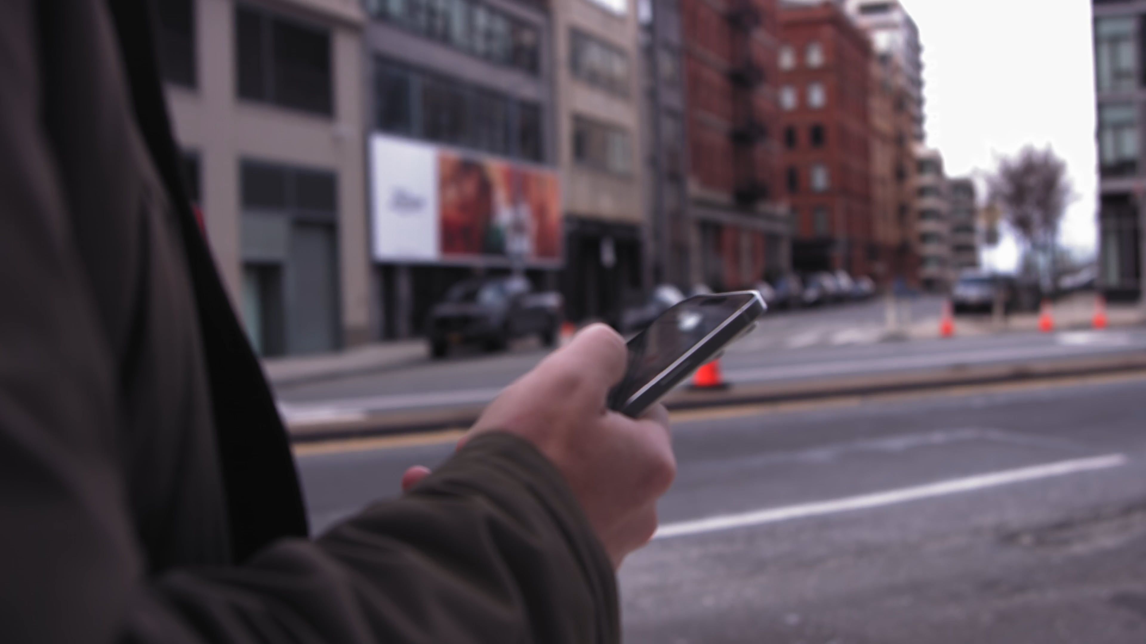 A person is using a cell phone while standing on a street Free Stock ...