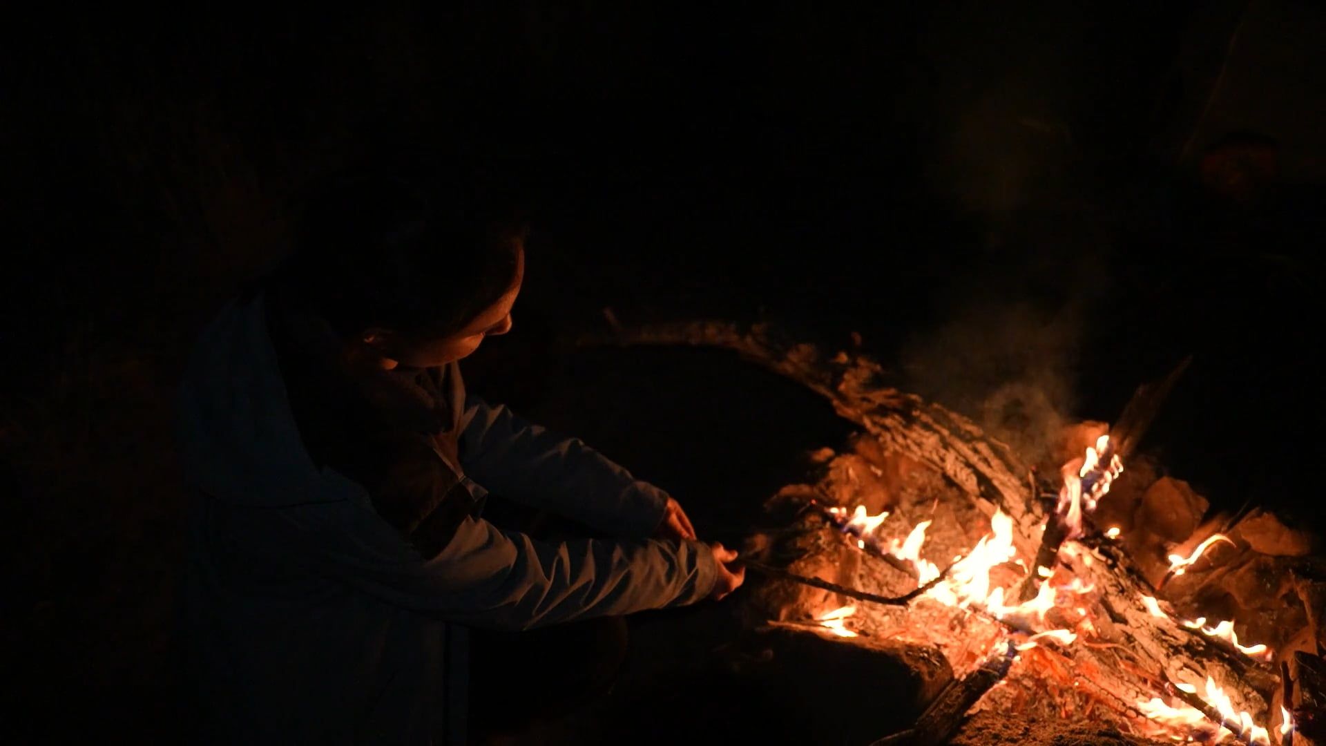A woman sitting by a campfire in the dark Free Stock Video Footage ...