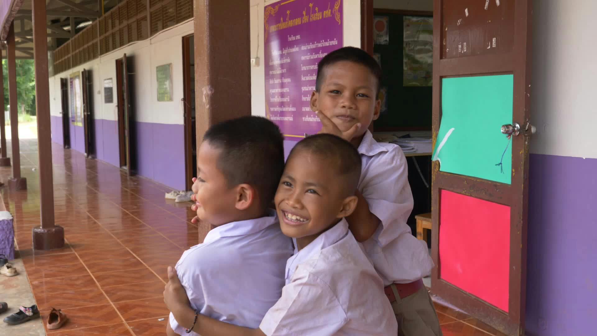 Three boys are smiling while standing in front of a building Free Stock ...