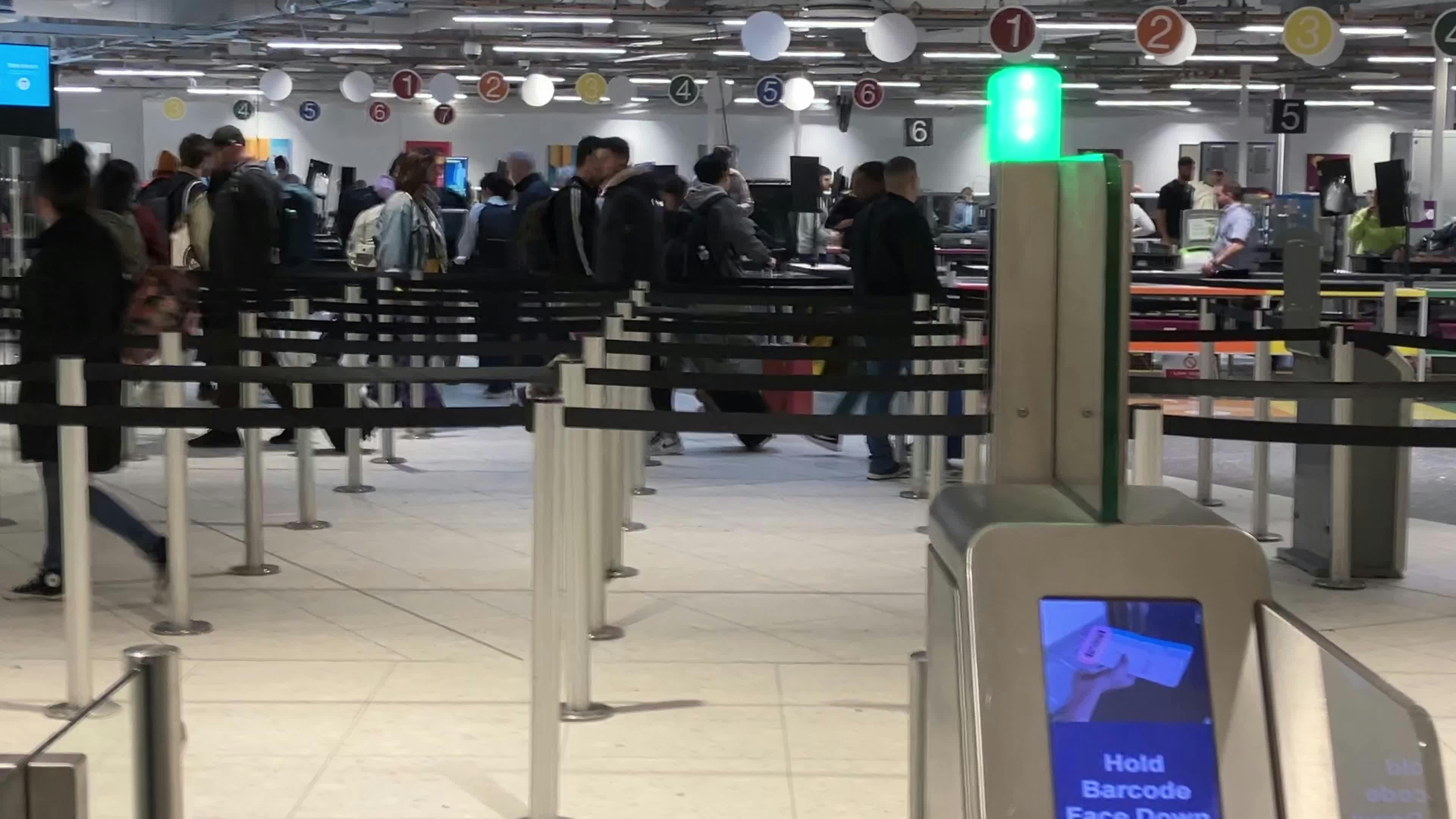 A security checkpoint at an airport with people walking through Free ...