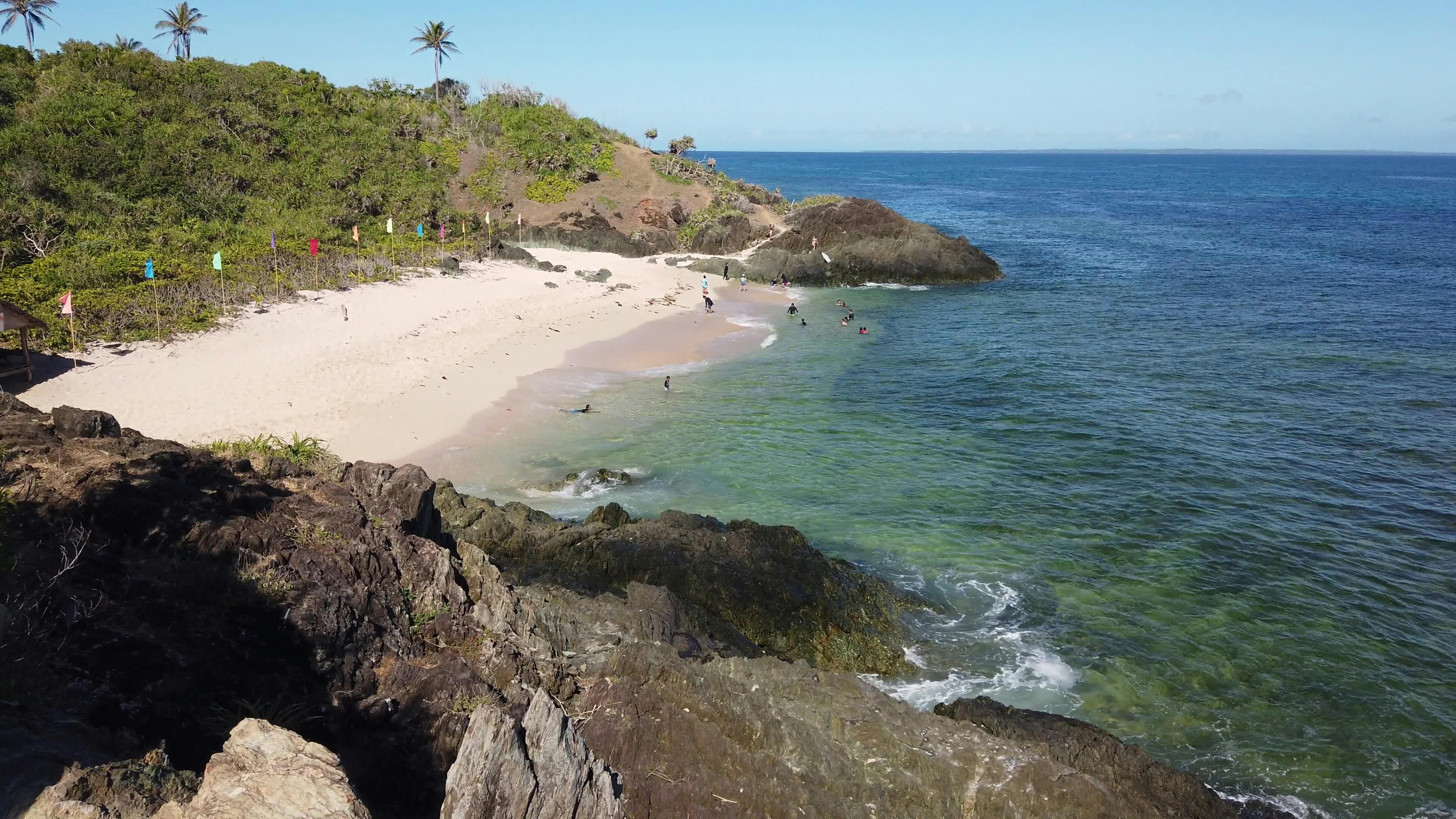 Clean Rocky Mini Cove Beach with Colored Flags and People Enjoying ...
