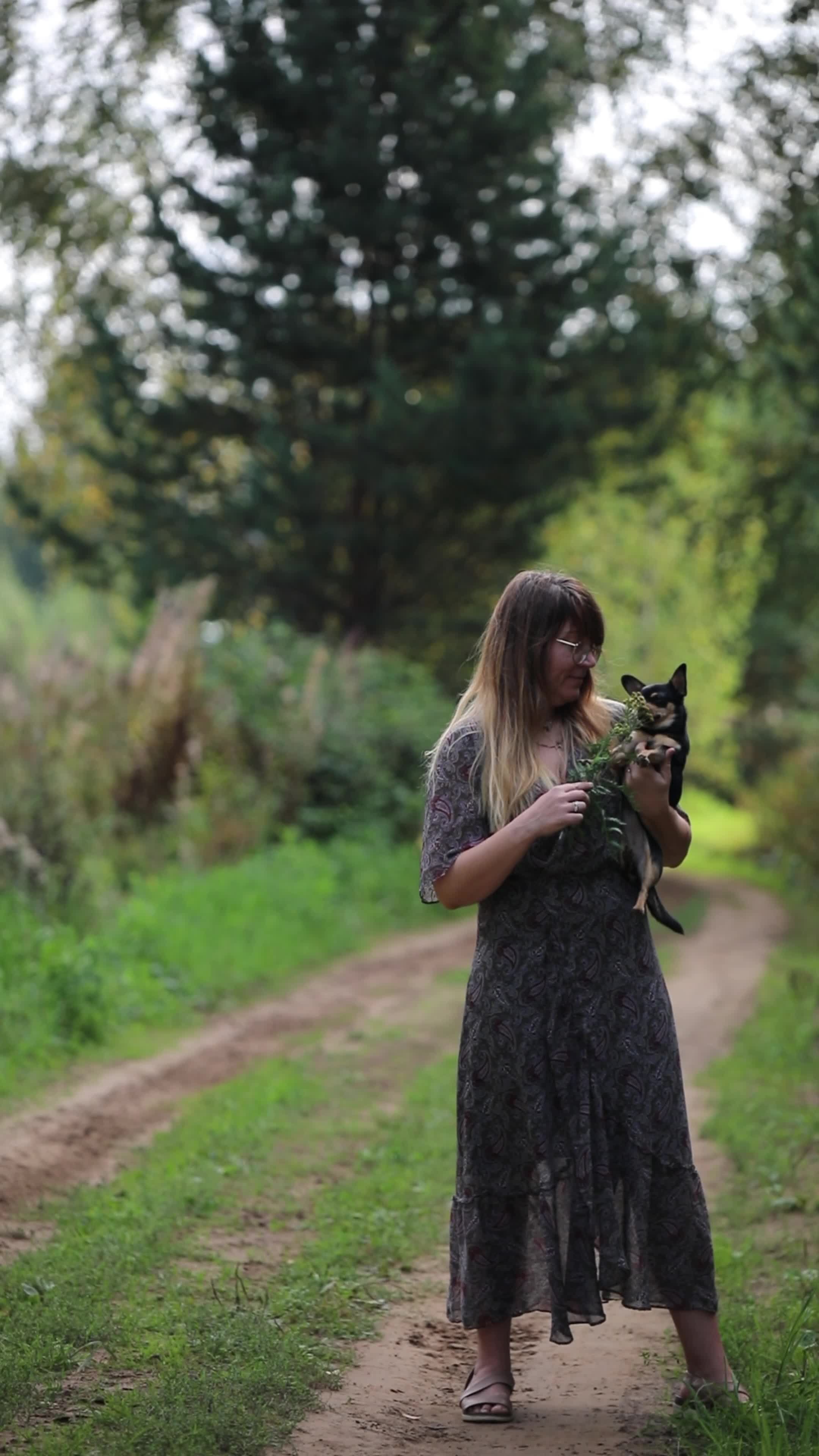 A woman in a dress holding a cat on a dirt road Free Stock Video ...