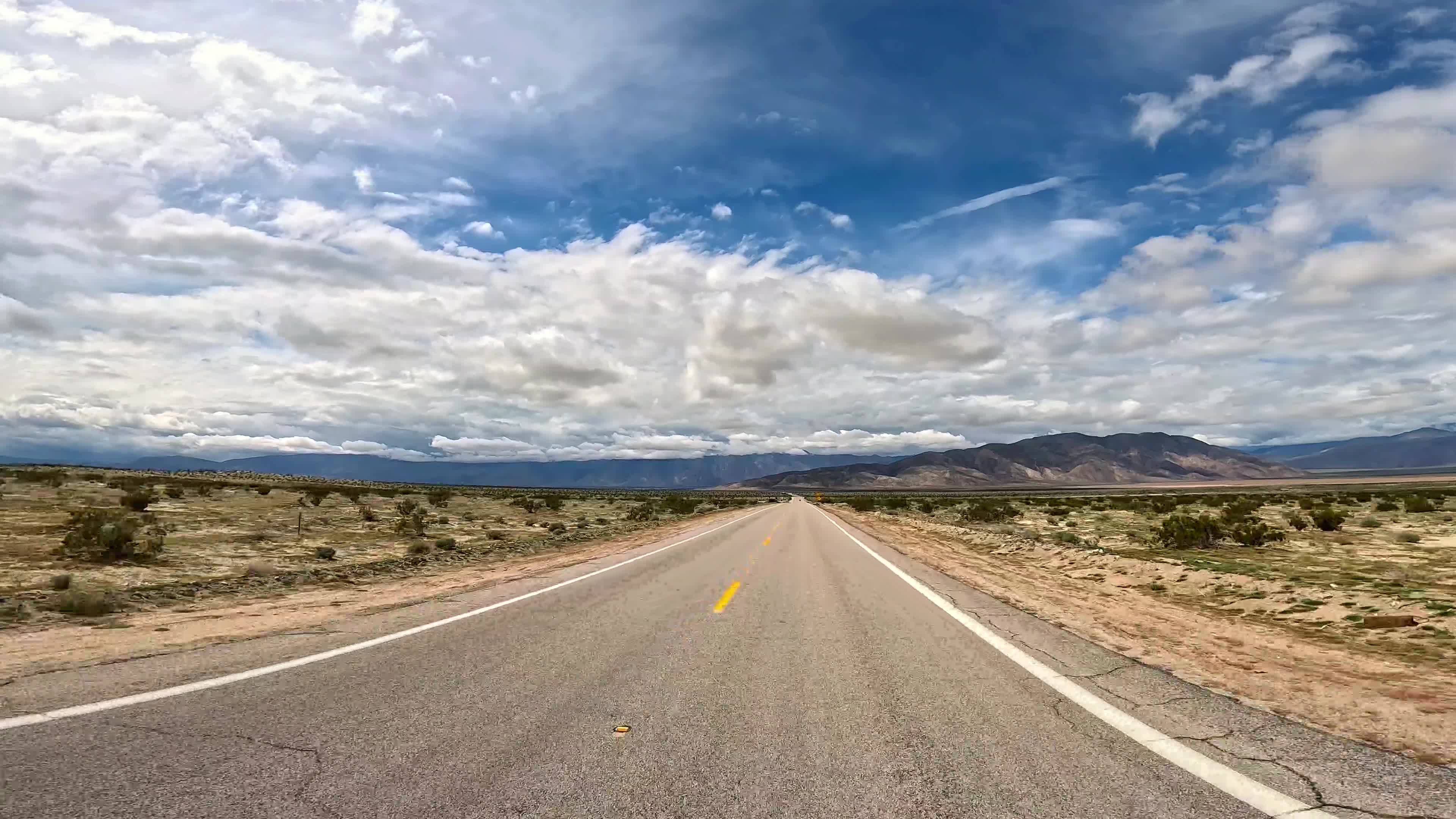 Uma Longa Estrada Vazia No Deserto Com Nuvens · Vídeo profissional gratuito