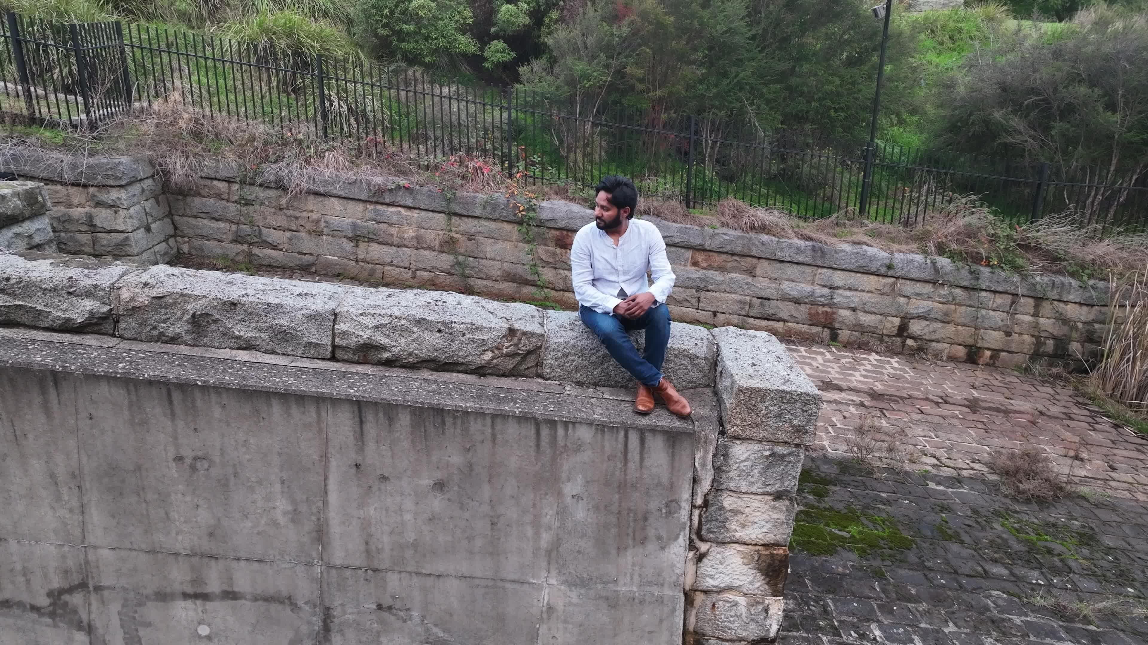 Relaxed Man Sitting on Stone Wall in Park Setting Free Stock Video ...