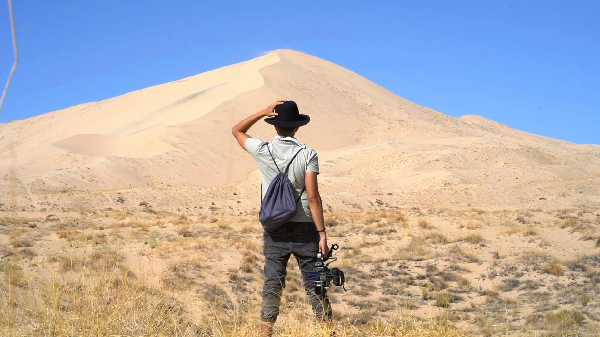 Back View Of A Man Holding A Camera Standing In Front Of A Sand Dune In ...