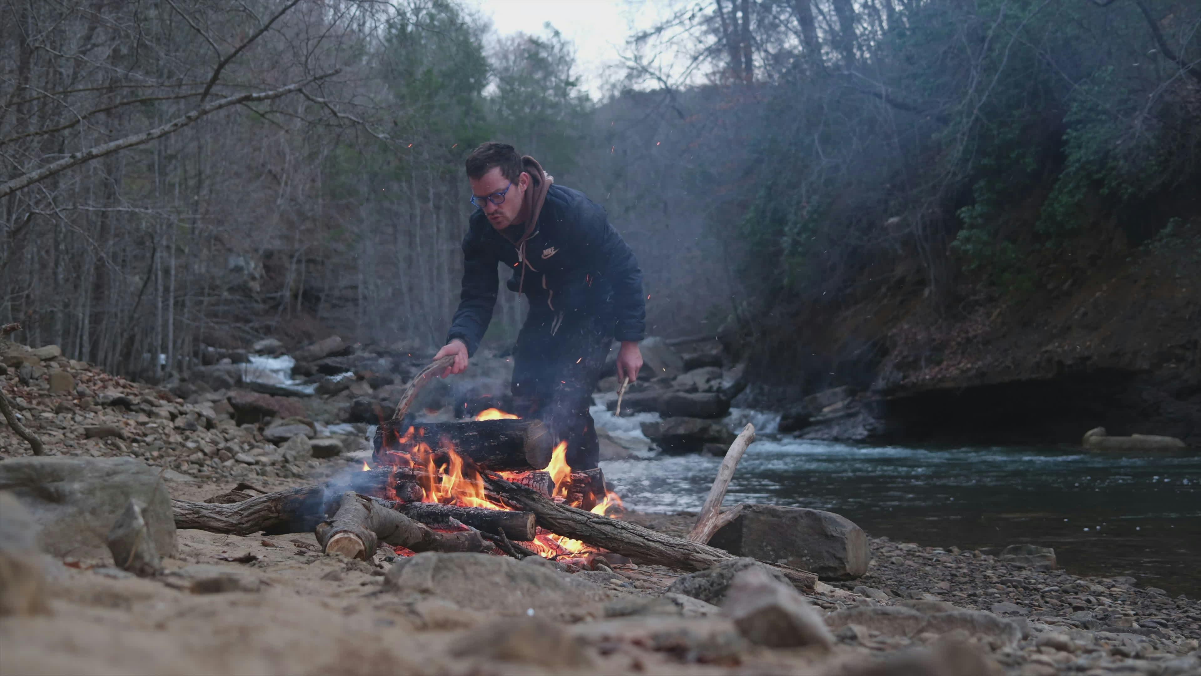 Man Tending Campfire Near a Forest Stream Free Stock Video Footage ...