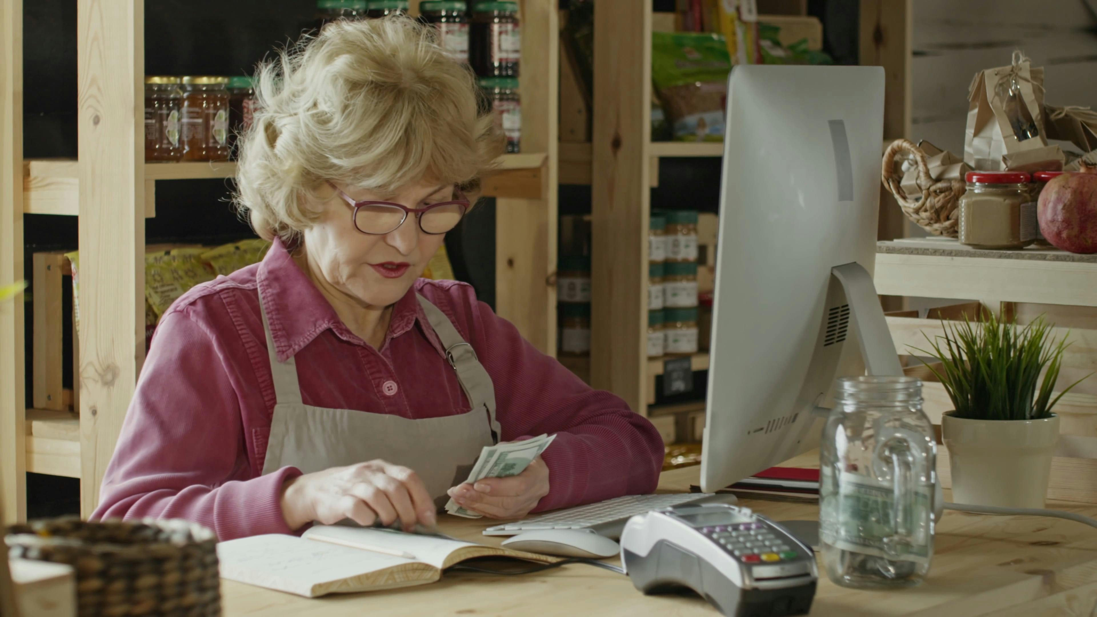 A Woman Busy Computing Money Behind The Counter Free Stock Video ...