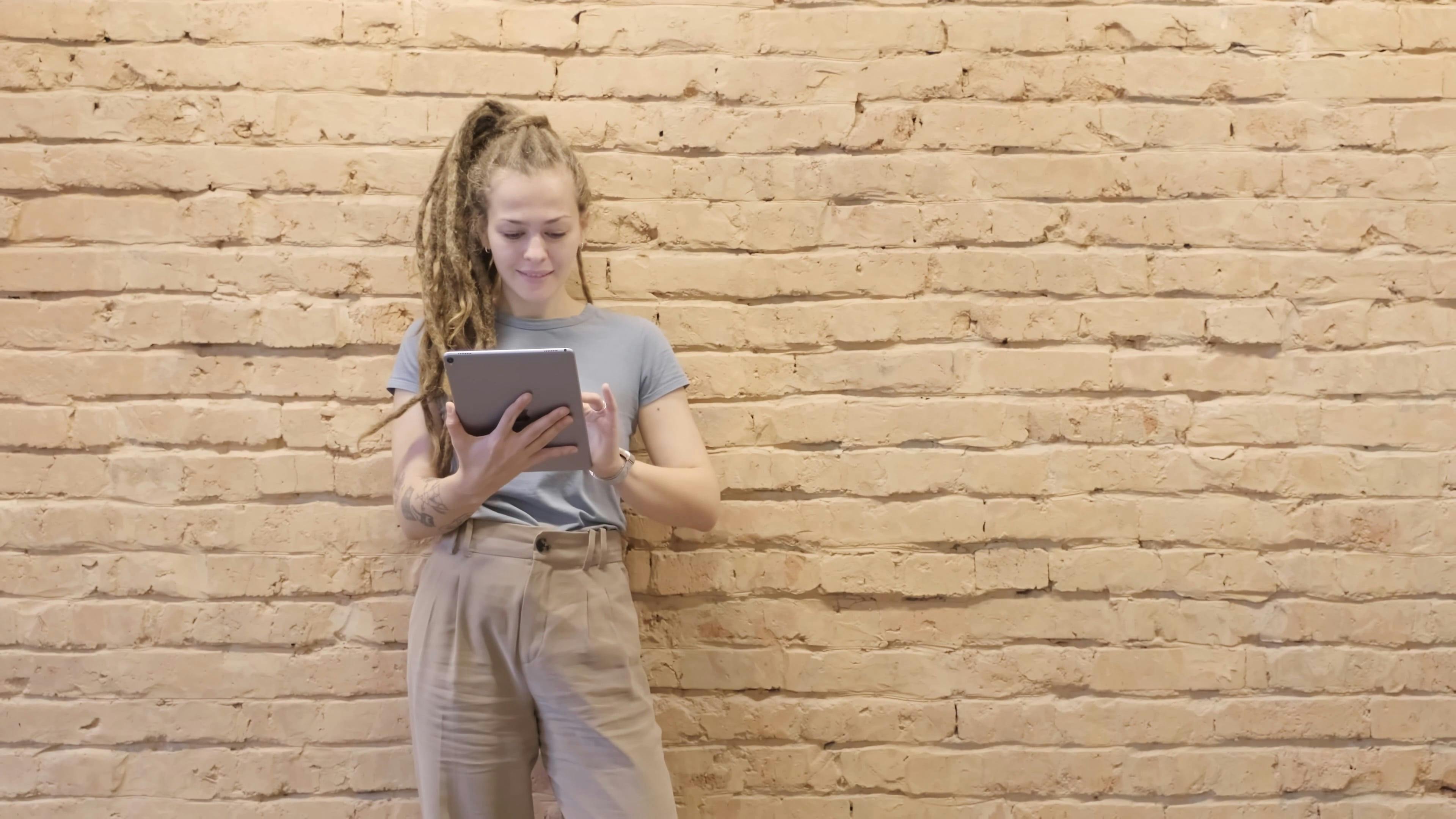 Woman Standing Near A Stonewall While Using Her Tablet · Free Stock Video