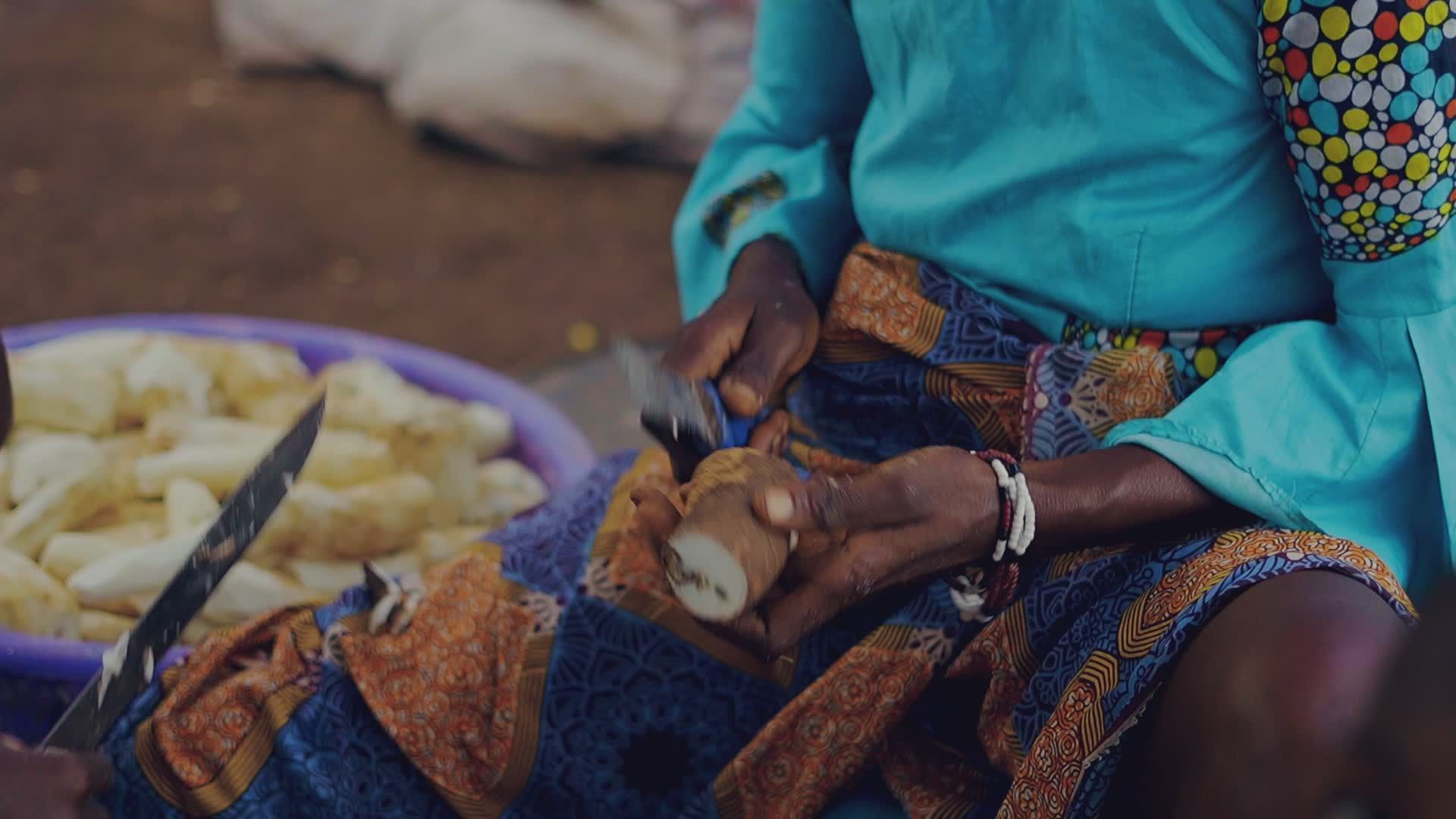 Woman Peeling Yams in Vibrant Traditional Attire Free Stock Video ...