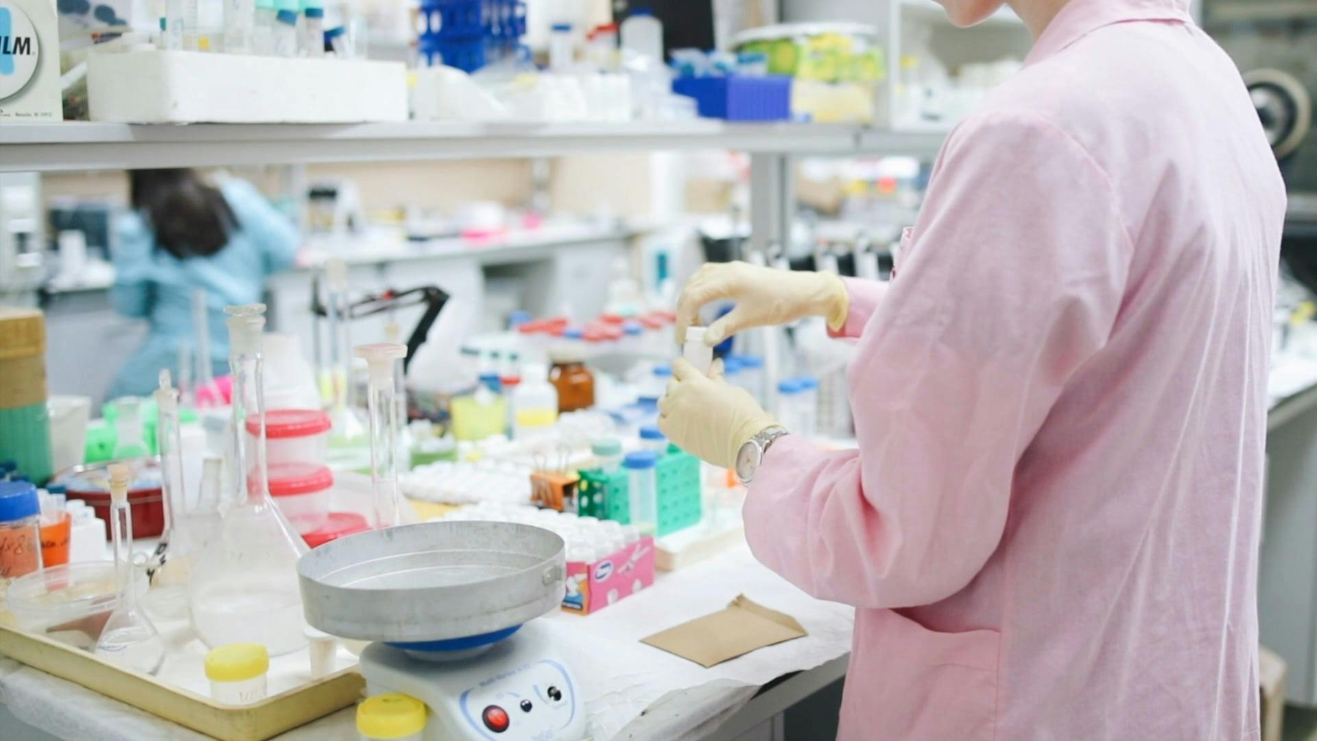 Woman In The Pink Laboratory Coat Opening A Chemical Sample · Free ...