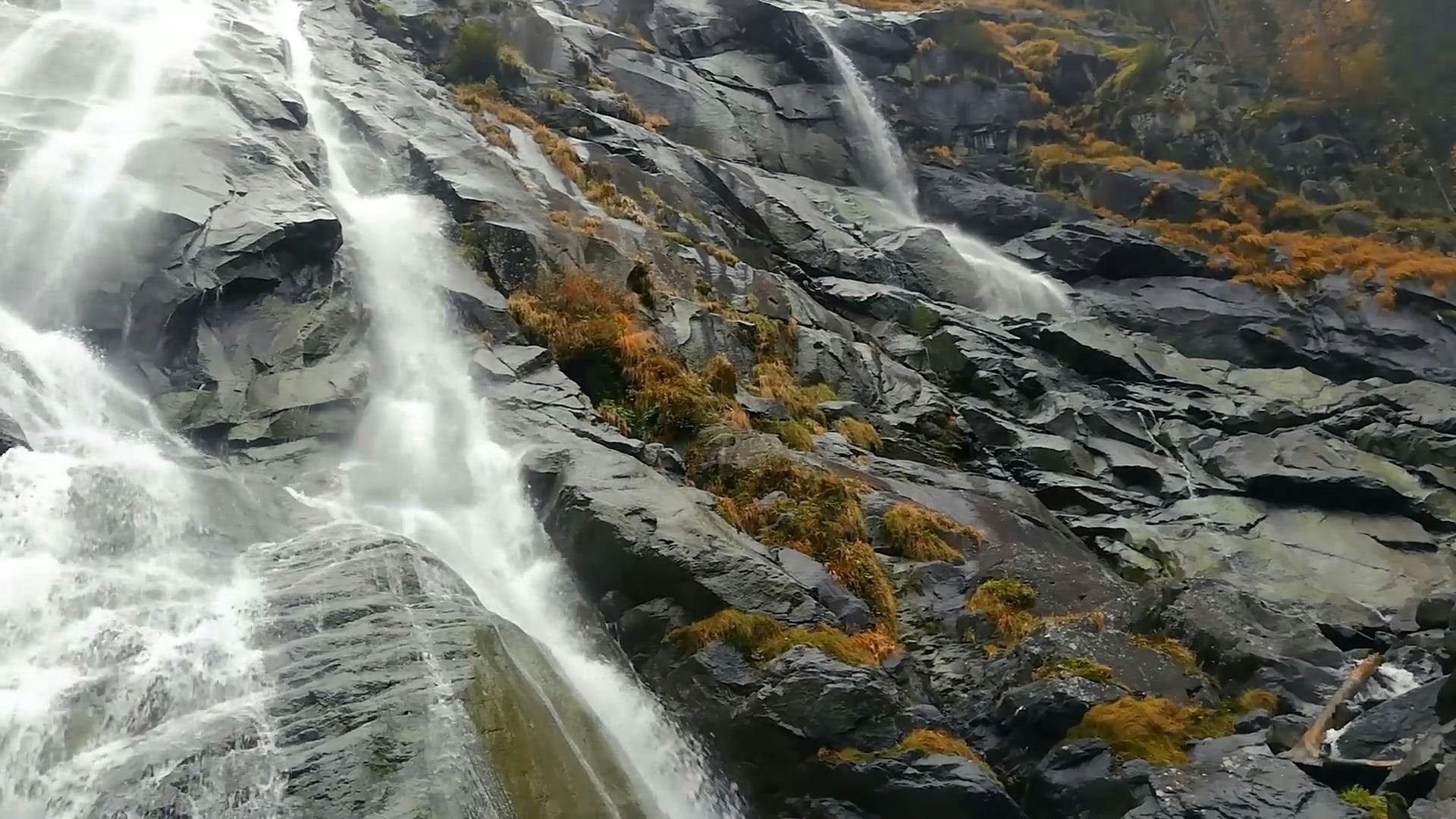 Cascading Waterfalls on a Mossy Rock Mountain Wall · Free Stock Video
