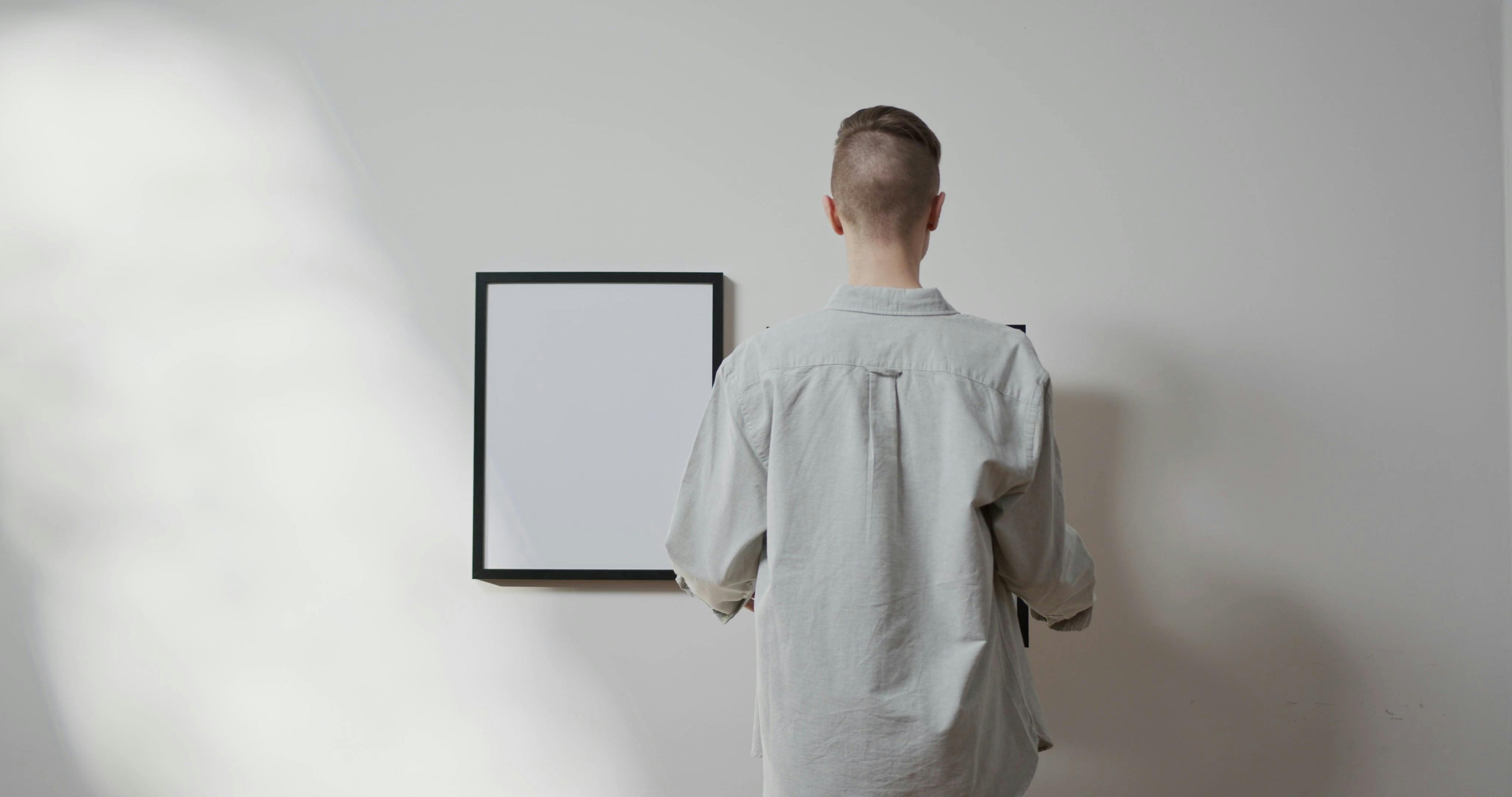 A Man Hanging A Picture Frame On A Wall · Free Stock Video