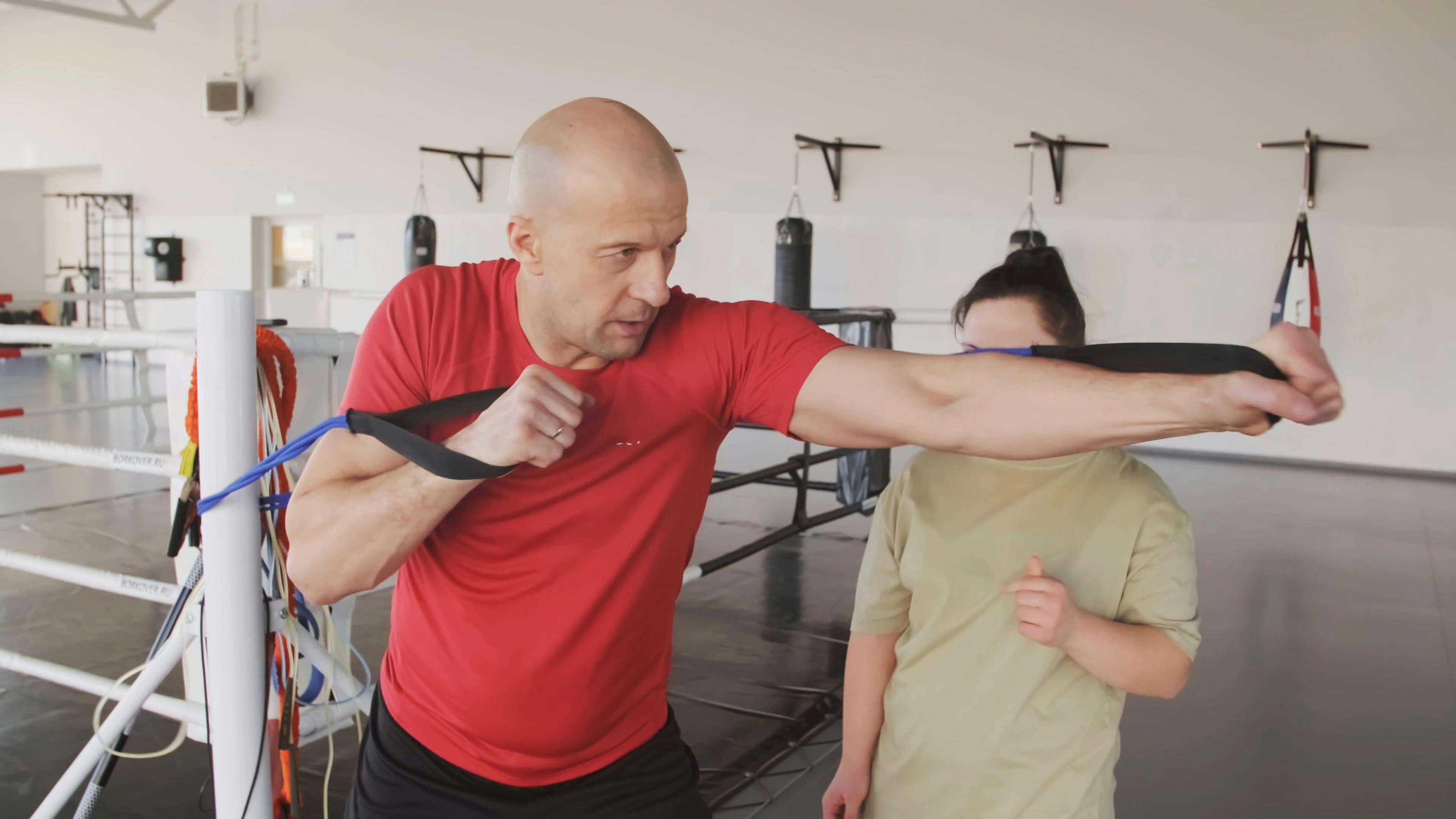 A Boxing Trainer Showing A Woman How To Use A Resistance Band · Free ...