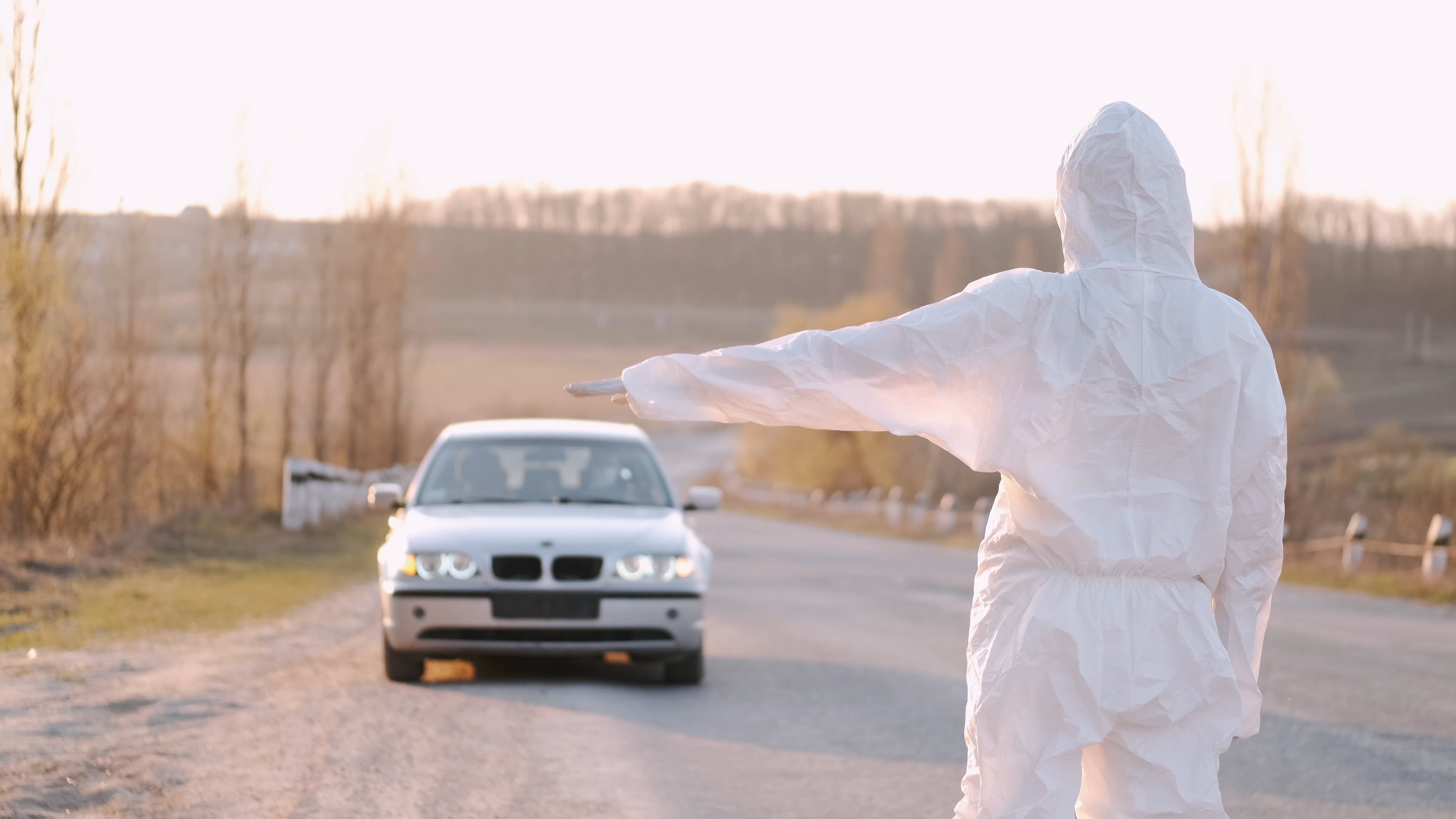 Person In a Hazmat Suit Signaling a Car to Stop · Free Stock Video