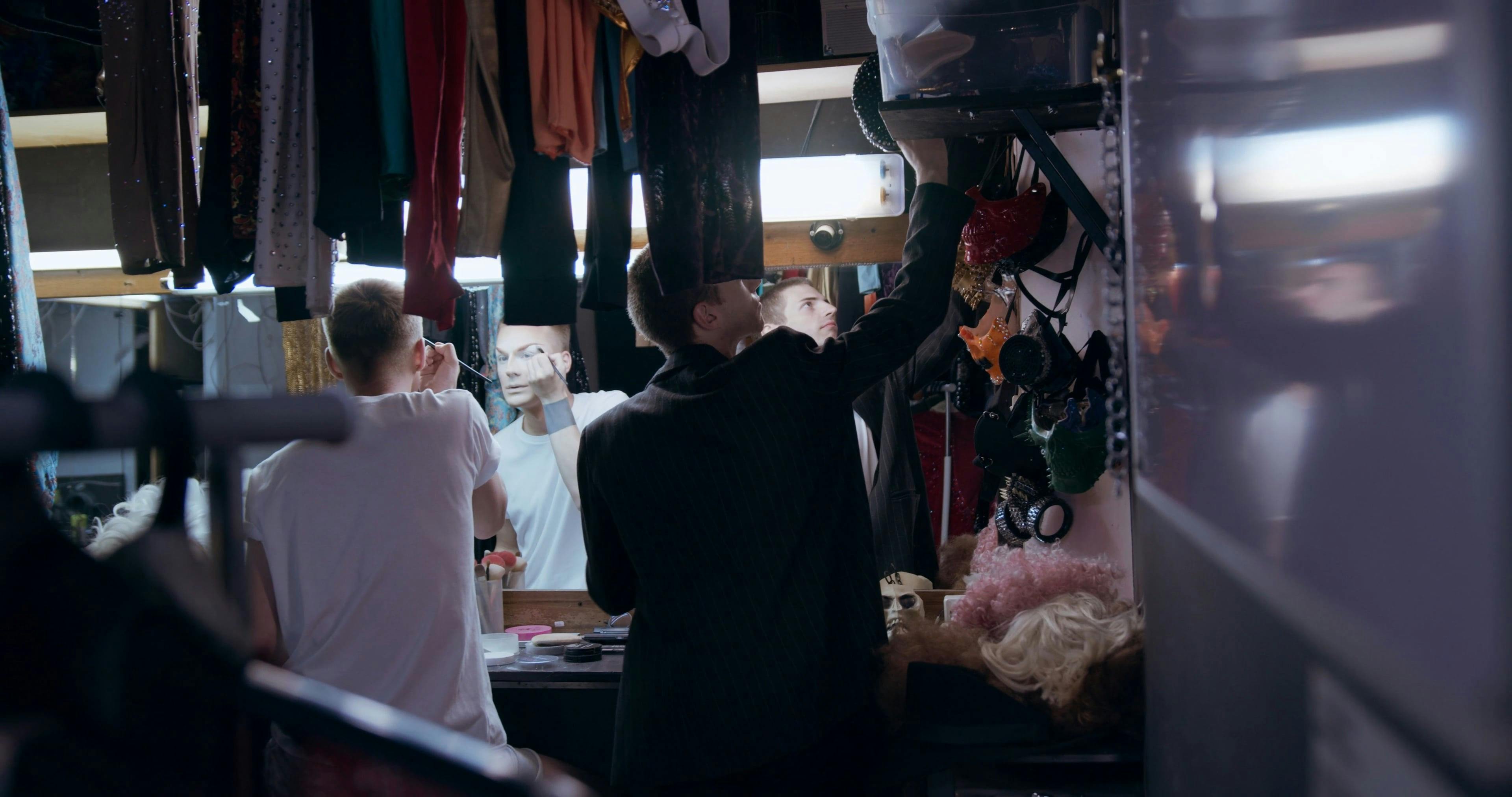 A man is standing in a room with clothes hanging on the wall Free Stock ...