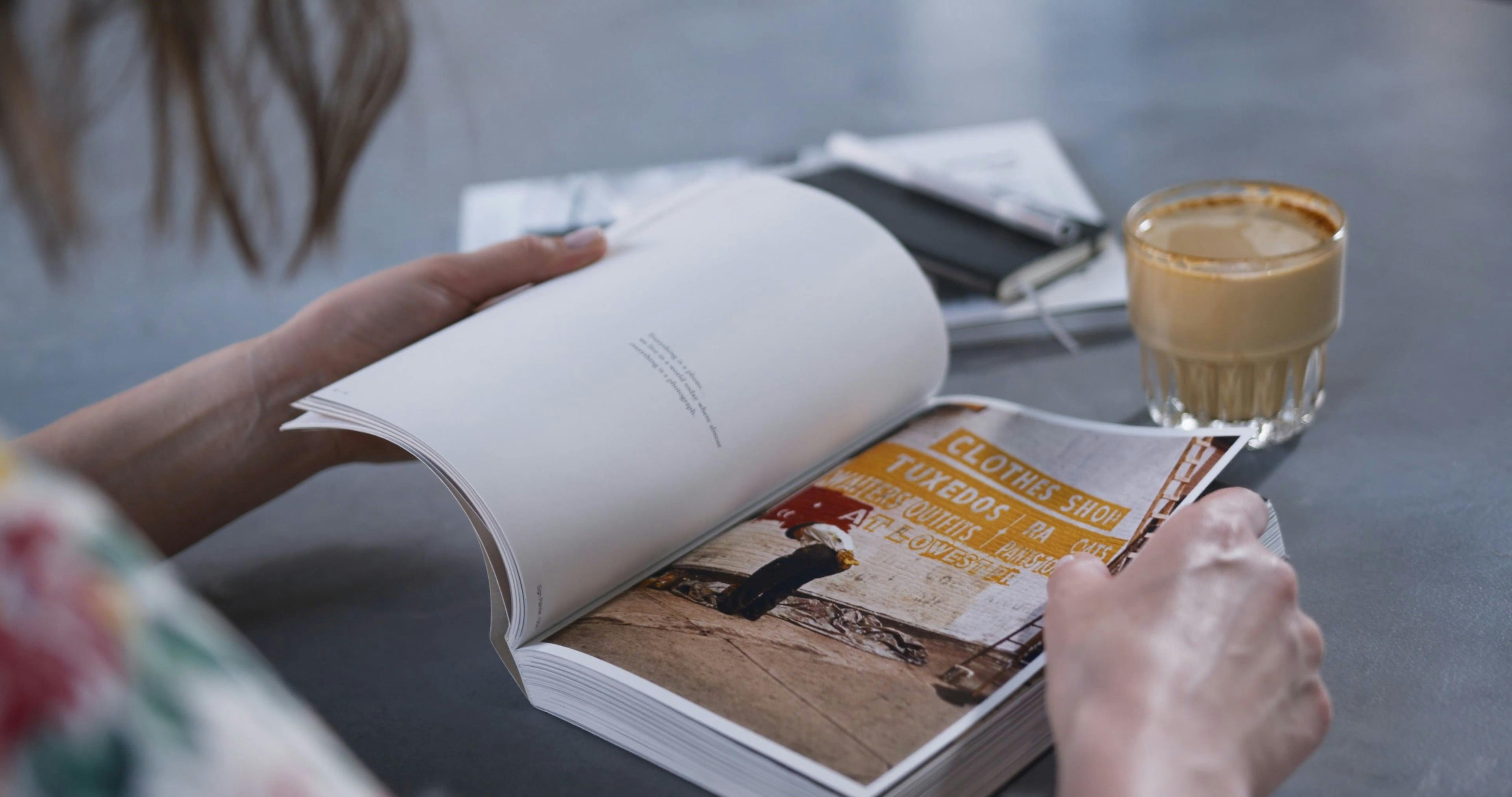 A Woman Browsing A Magazine While Drinking Coffee · Free Stock Video