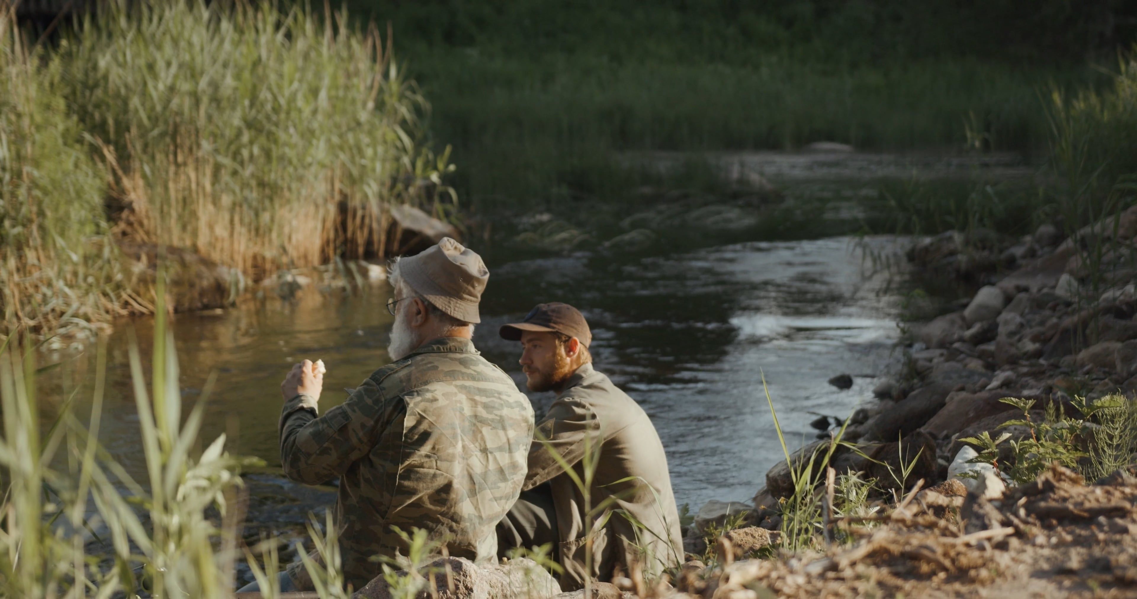 Two Men Sitting by the River Bank While Eating Free Stock Video Footage ...