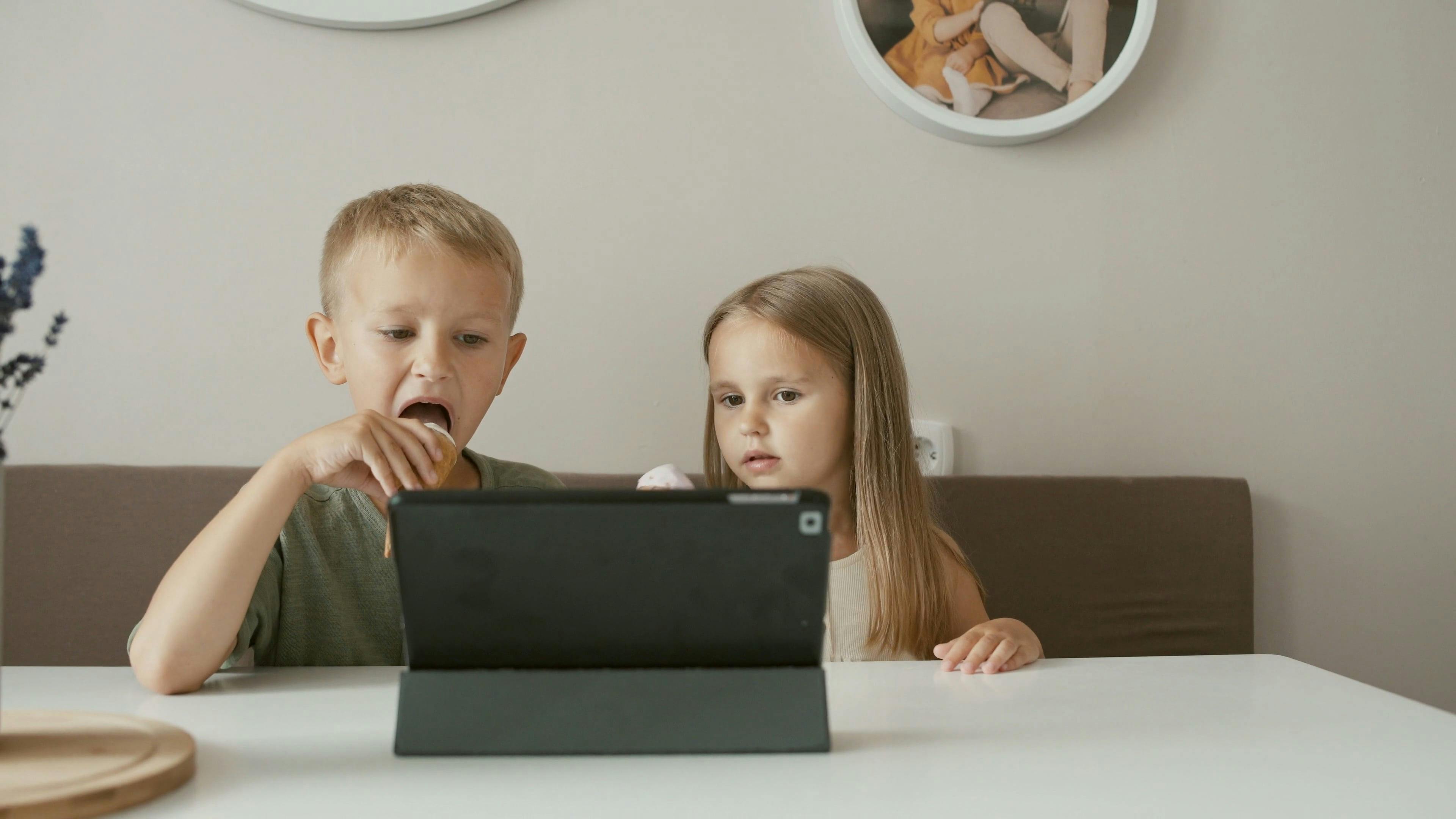 Children Eating Ice Cream While Looking at Screen of a Tablet Free ...