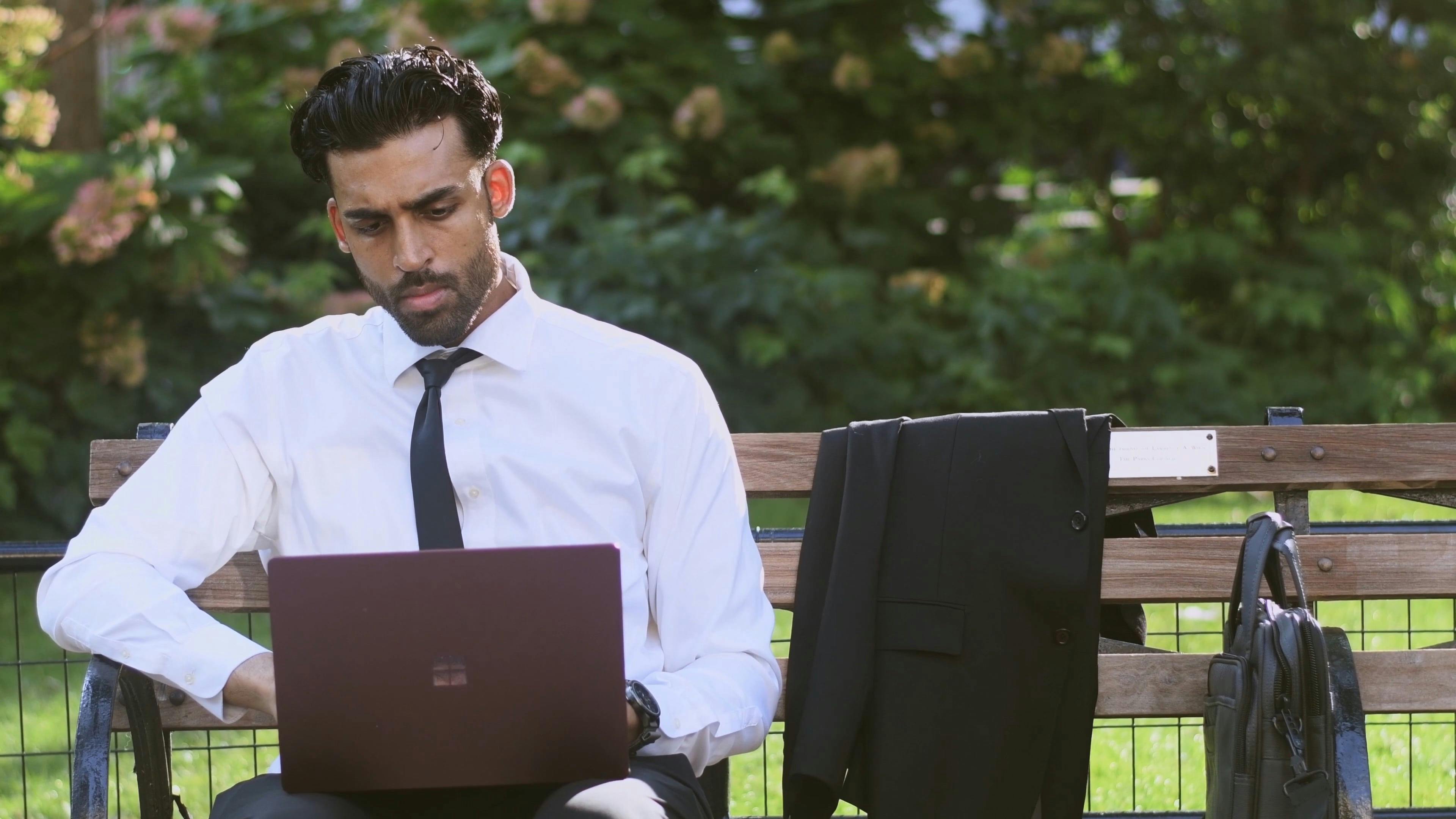 A Man Working while Sitting on a Bench · Free Stock Video