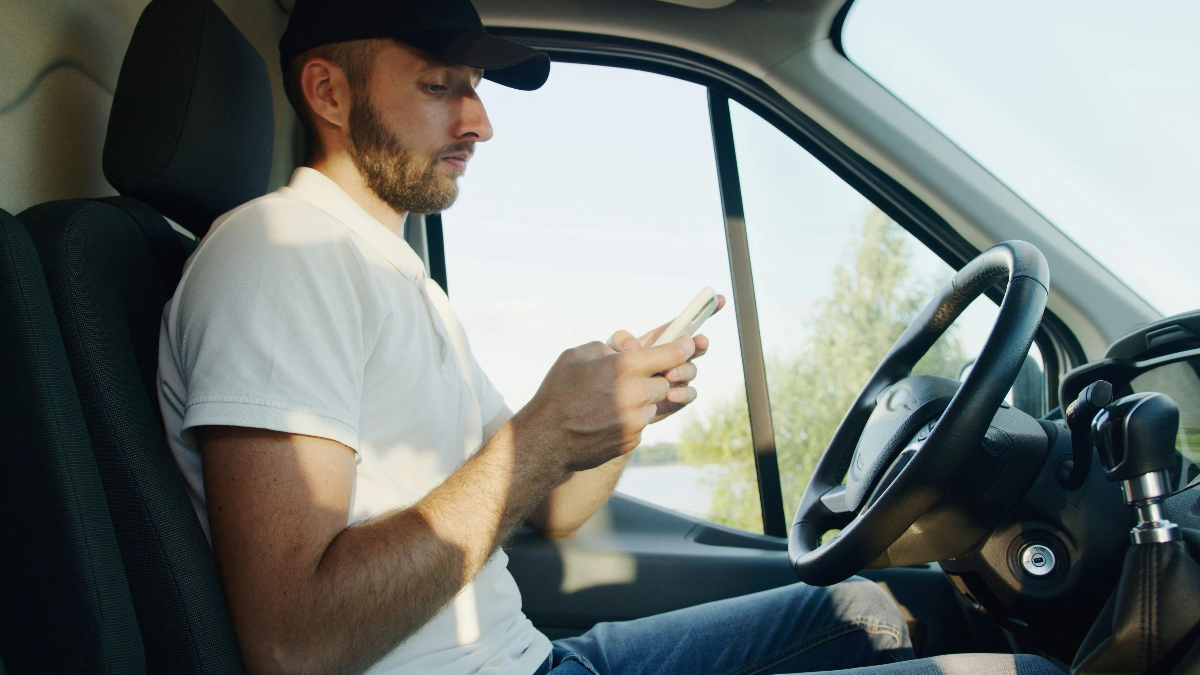 A Delivery Man Sitting Inside the Vehicle while Using His Smartphone ...