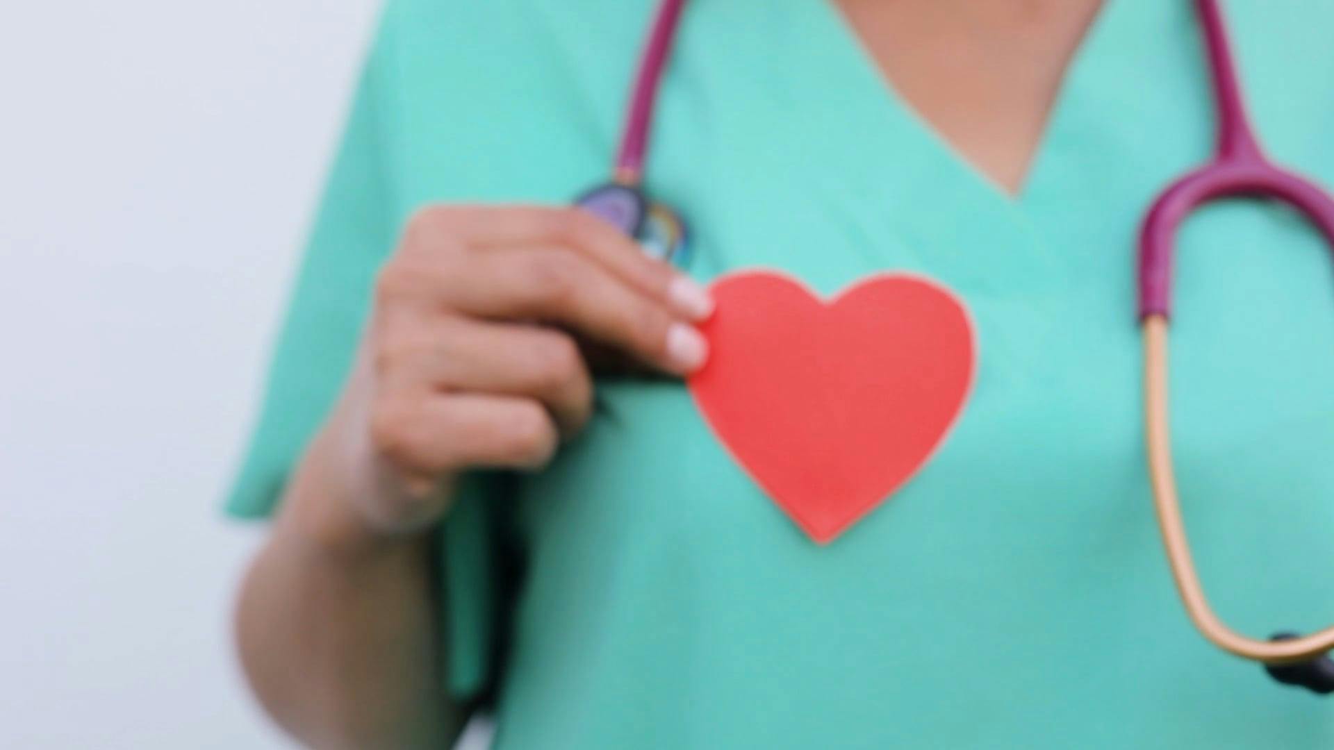 A Female Doctor Holding a Heart Cut out over her Chest Free Stock Video ...