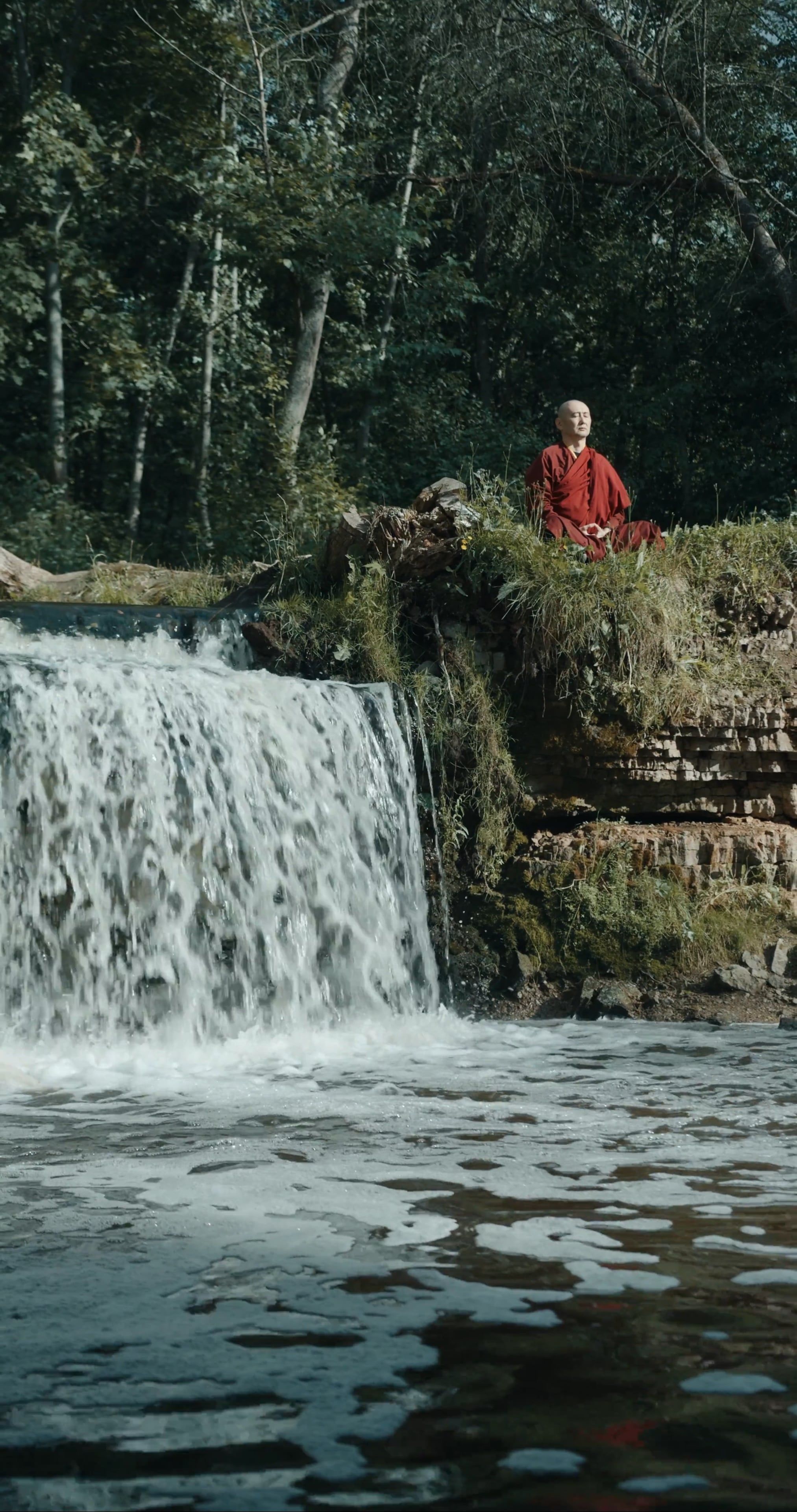 A Monk Meditating Near A Waterfall · Free Stock Video